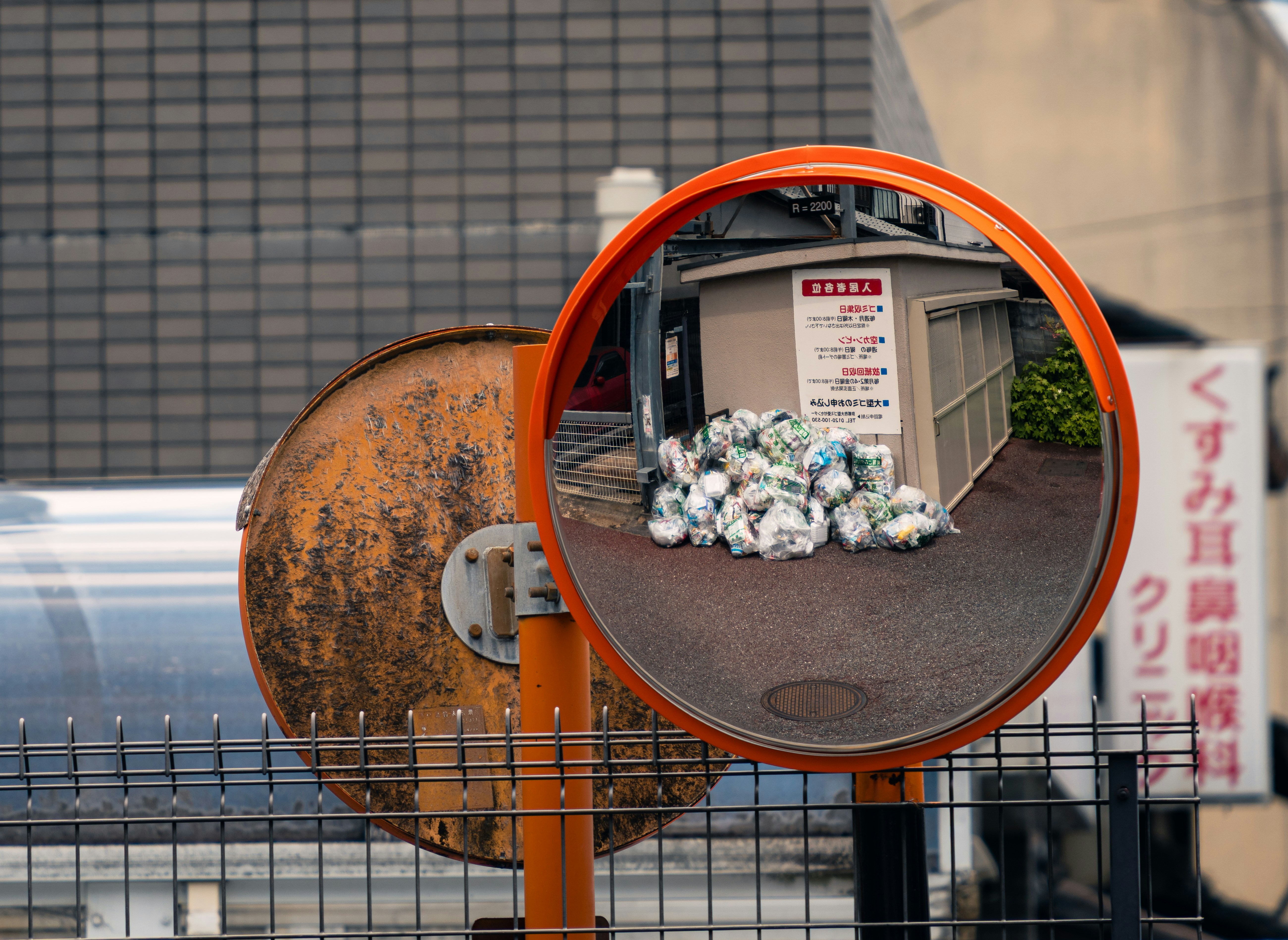 Mirrored Street: Trash Bags Reflected in the Circular Red Mirror