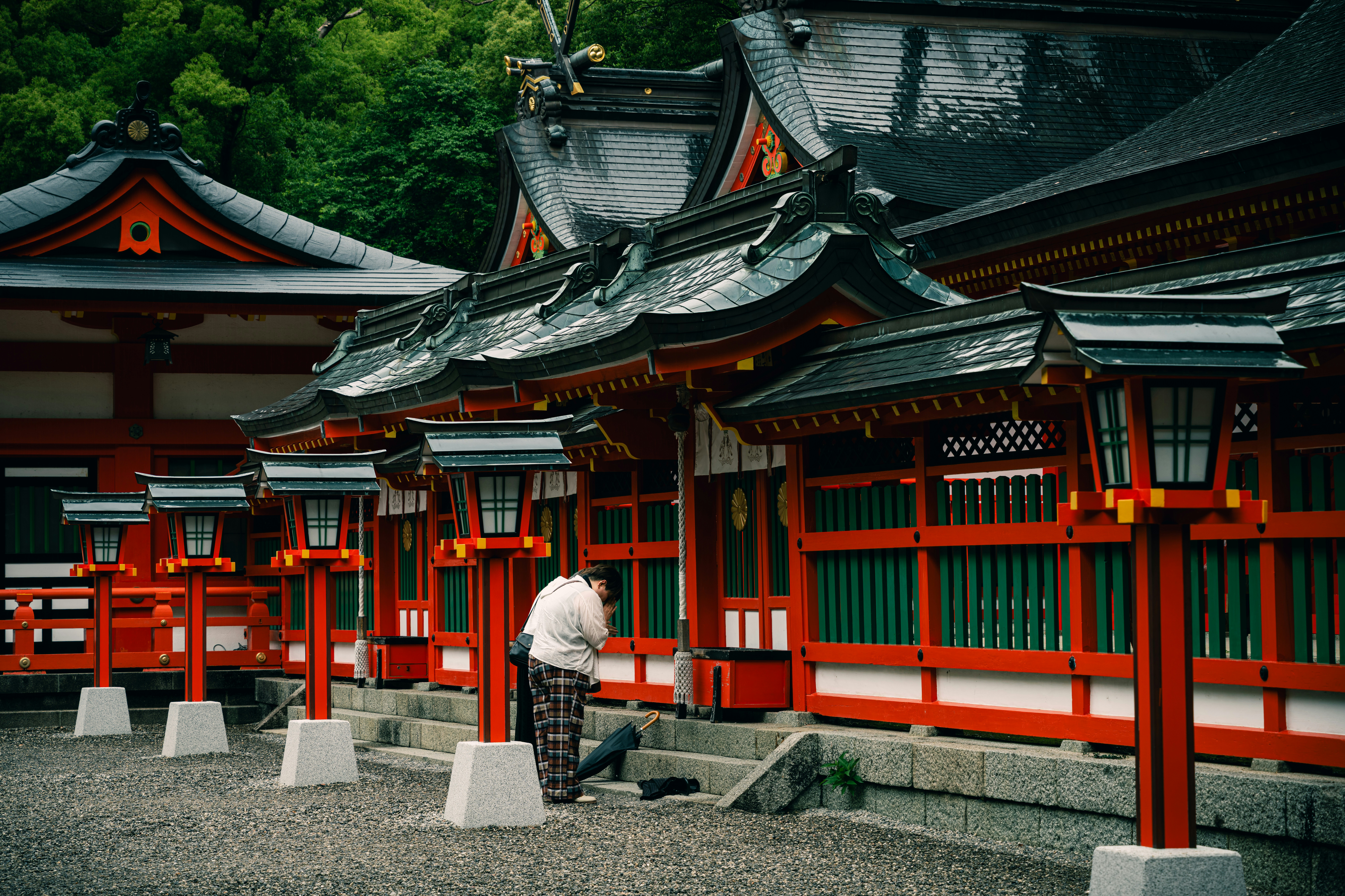 Traditional japanese shrine with red lanterns and a person.