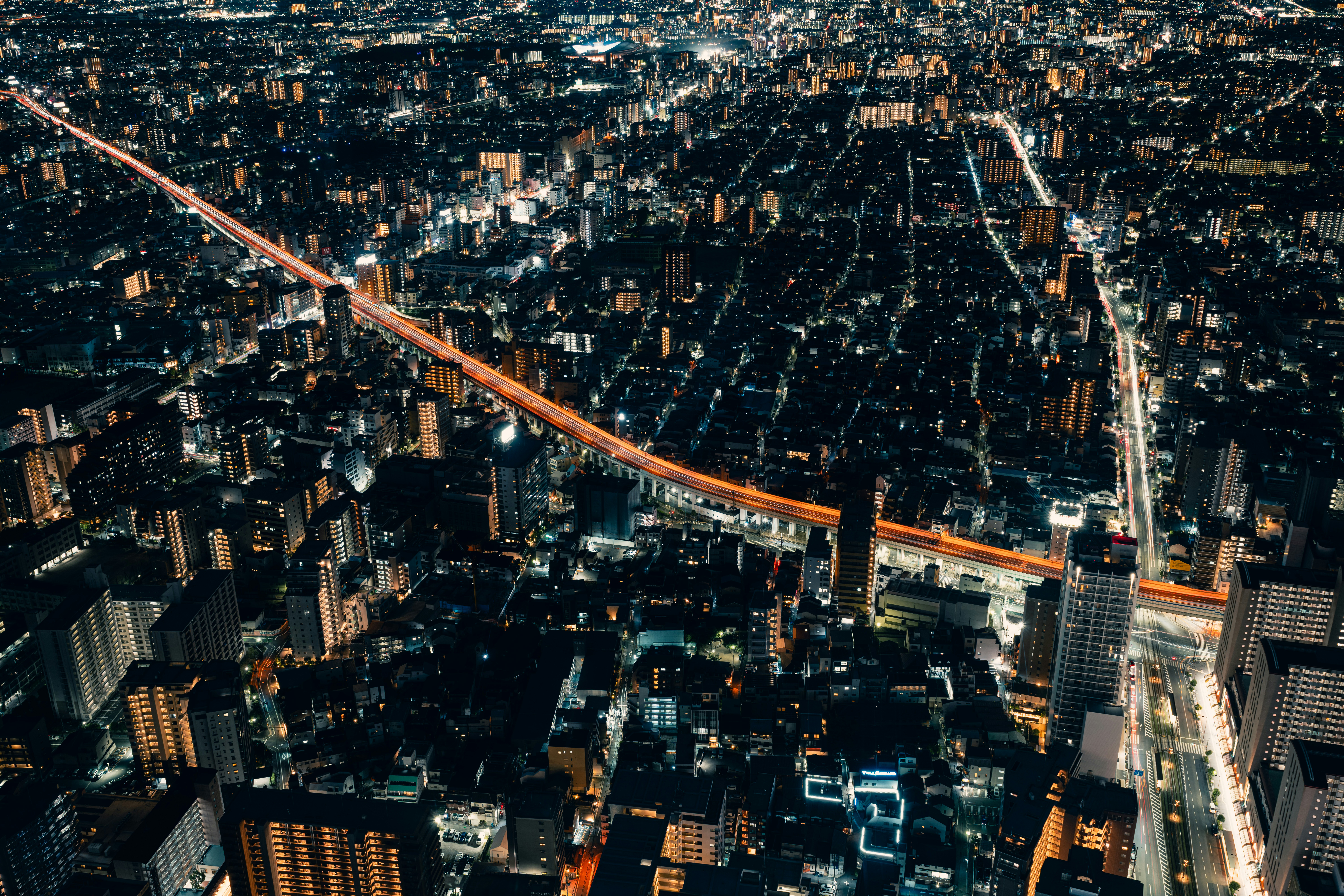 Nightflight Over a Neon Grid: Aerial Cityscape with a Distant Ribbon of Traffic
