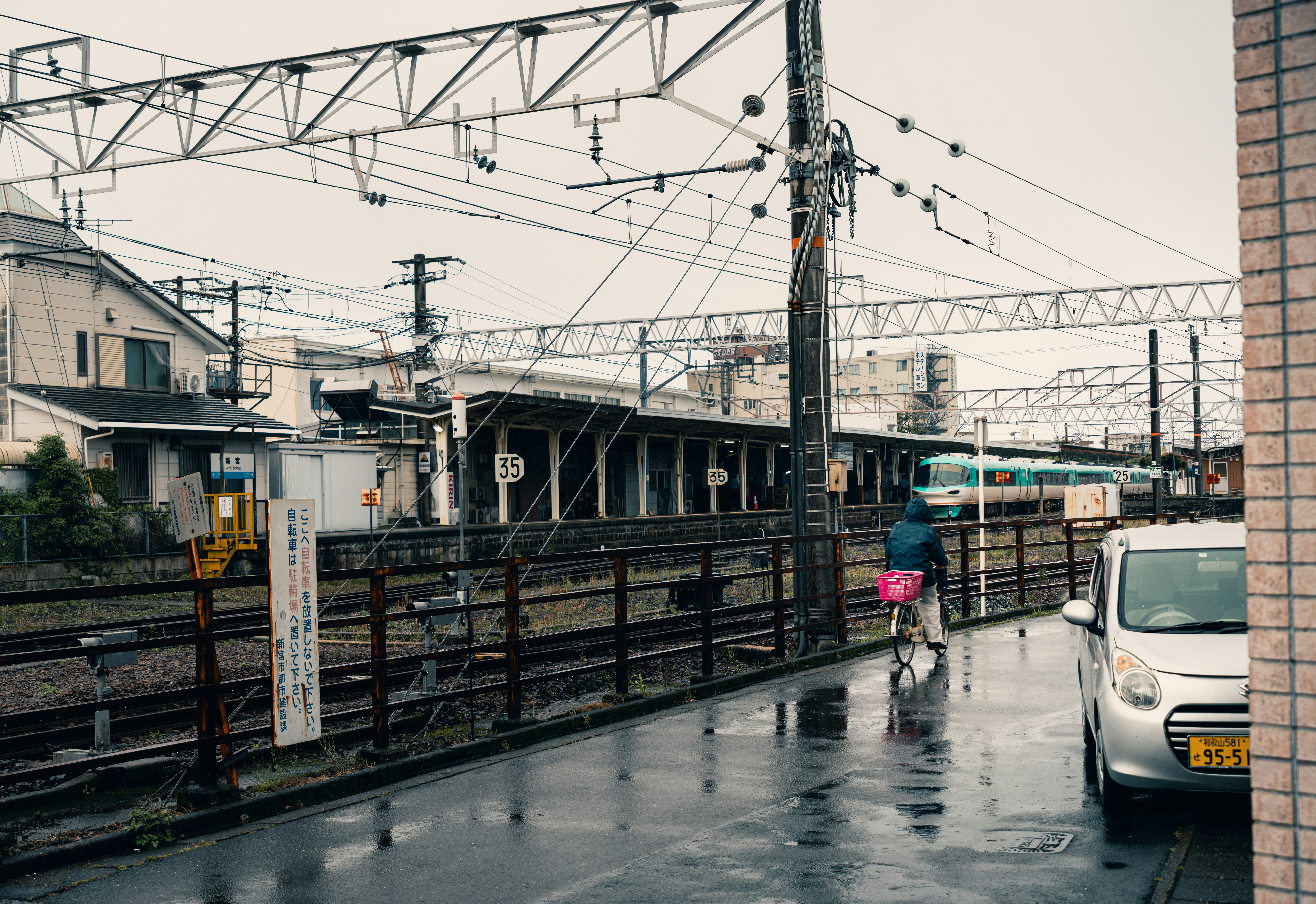 Person with umbrella on wet train platform, train in background.