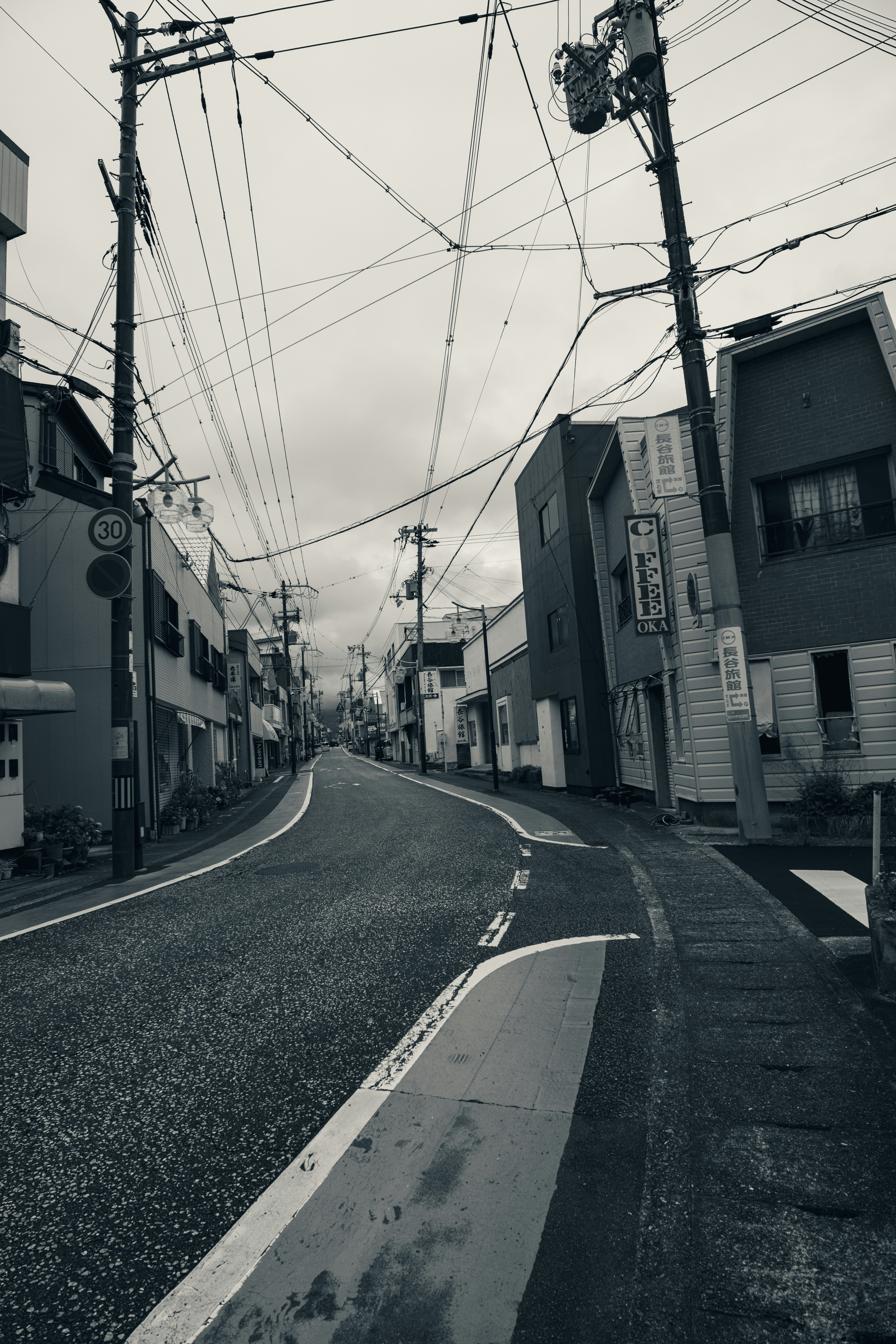 Black and white street scene with utility poles and buildings.