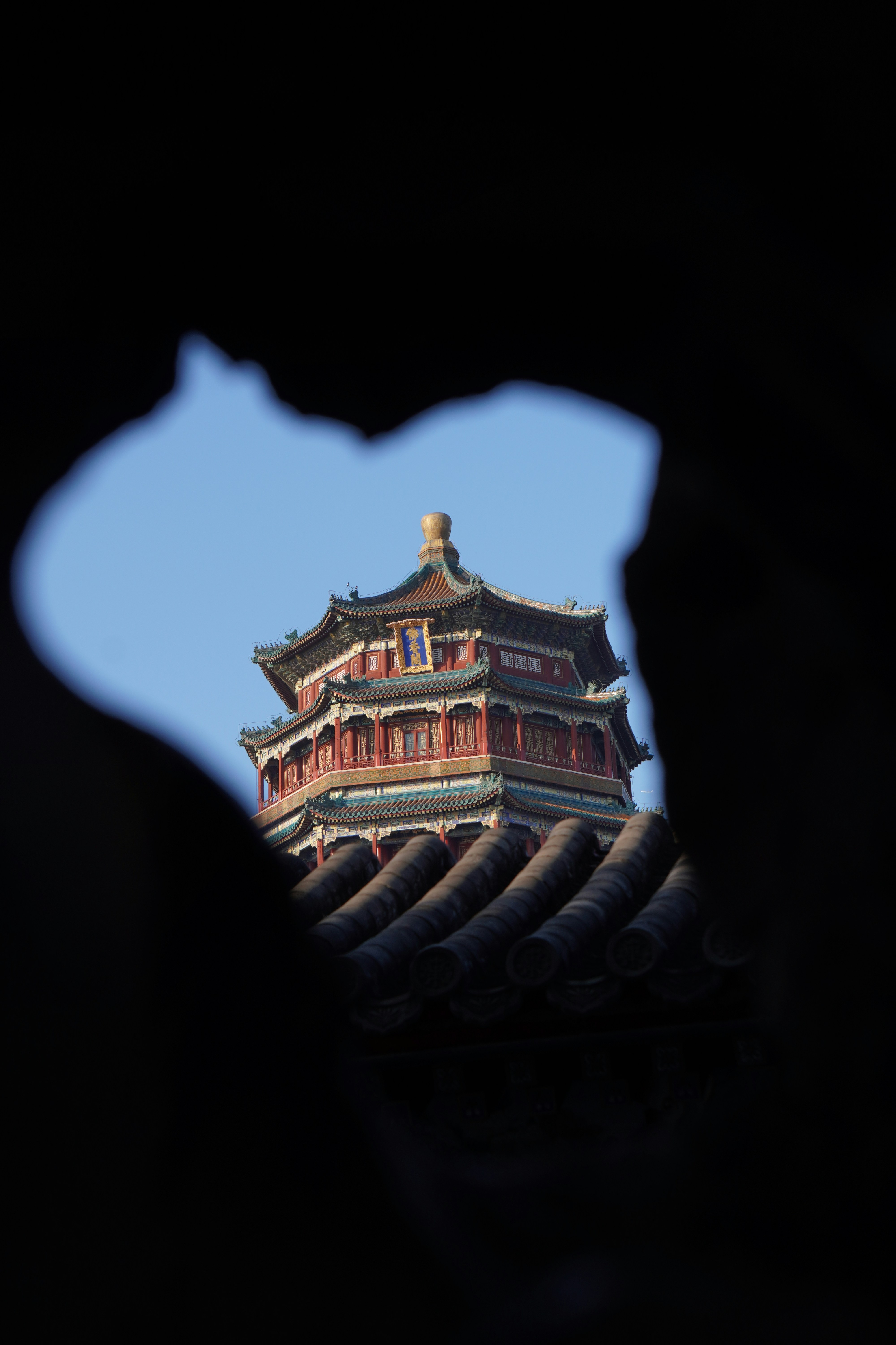 Hidden Pagoda: Red-Tiered Roof Peeking Through a Window of Darkness