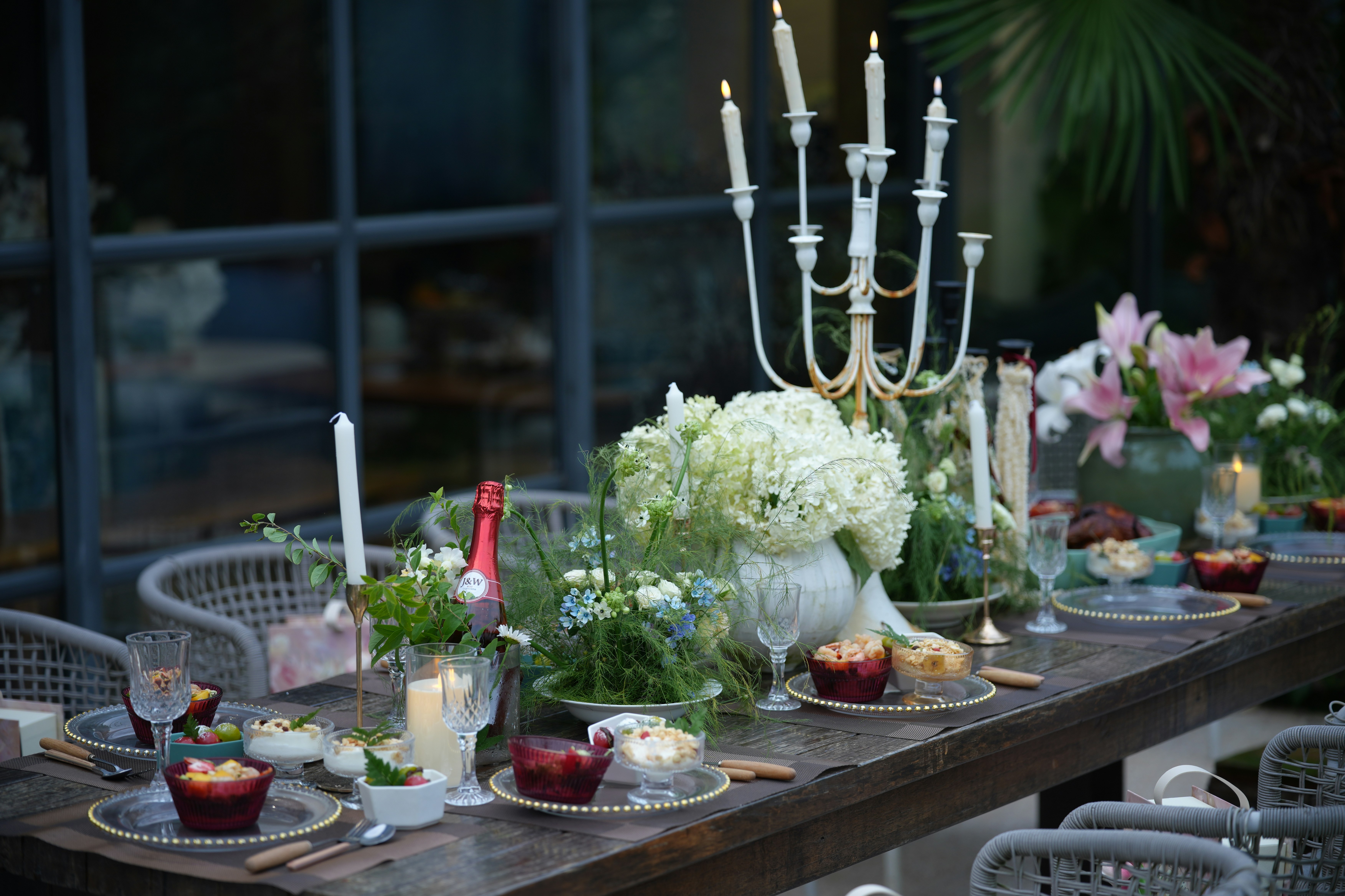 An elegant outdoor dining table set with candles and flowers.