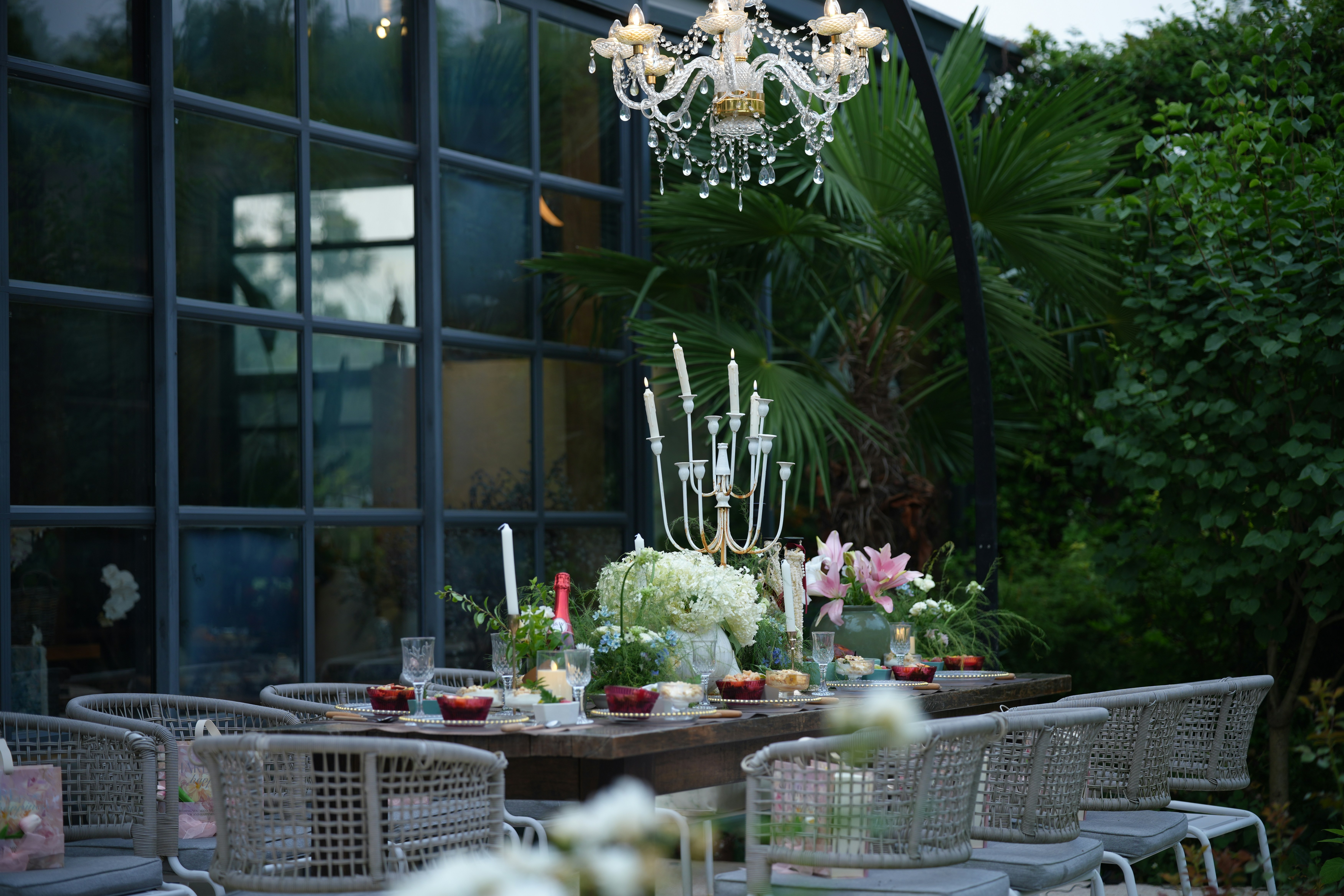 Elegant outdoor dining table with chandelier and floral decorations.