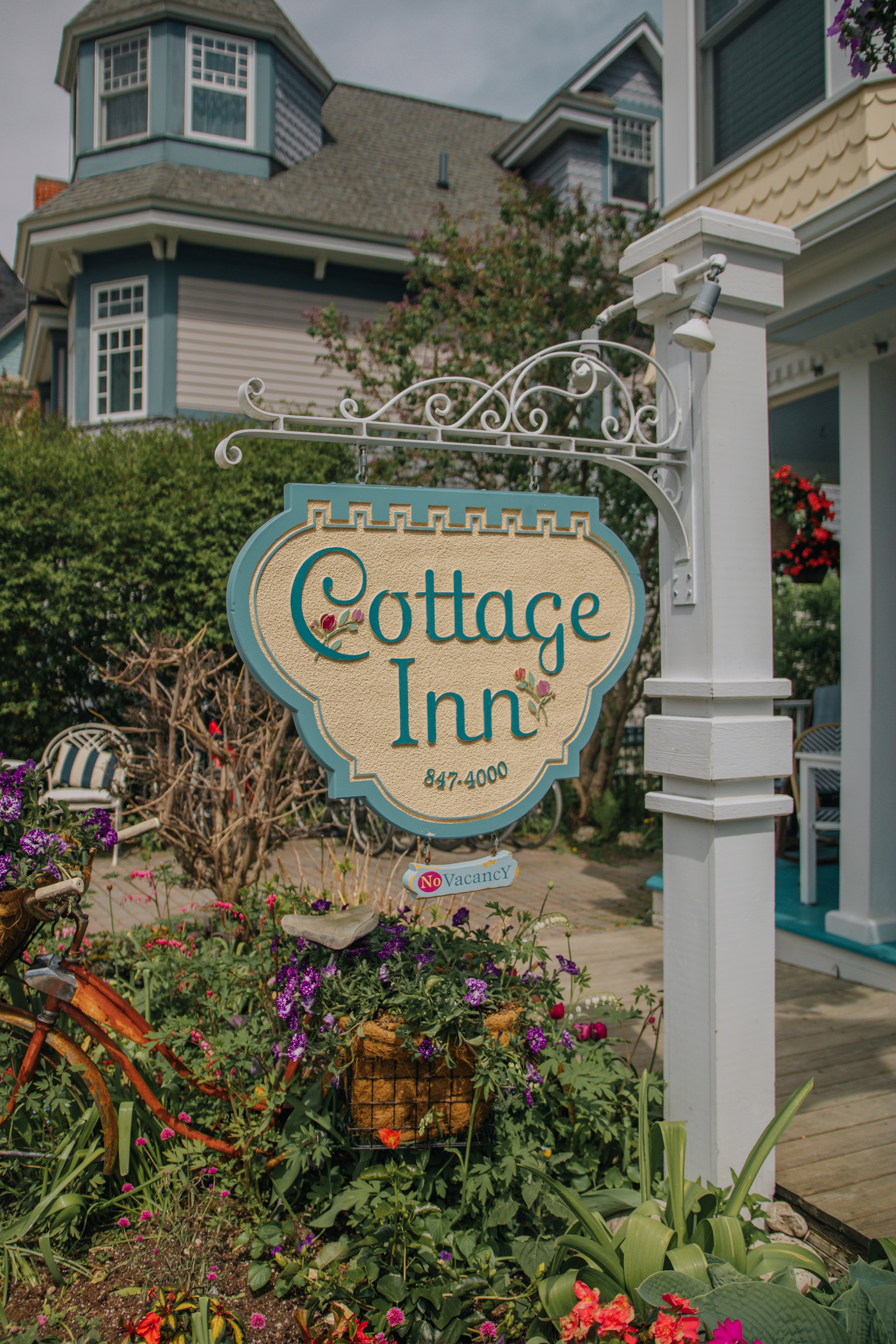 Cottage Inn Sign Framed by Floral Bed and Vintage Bicycles