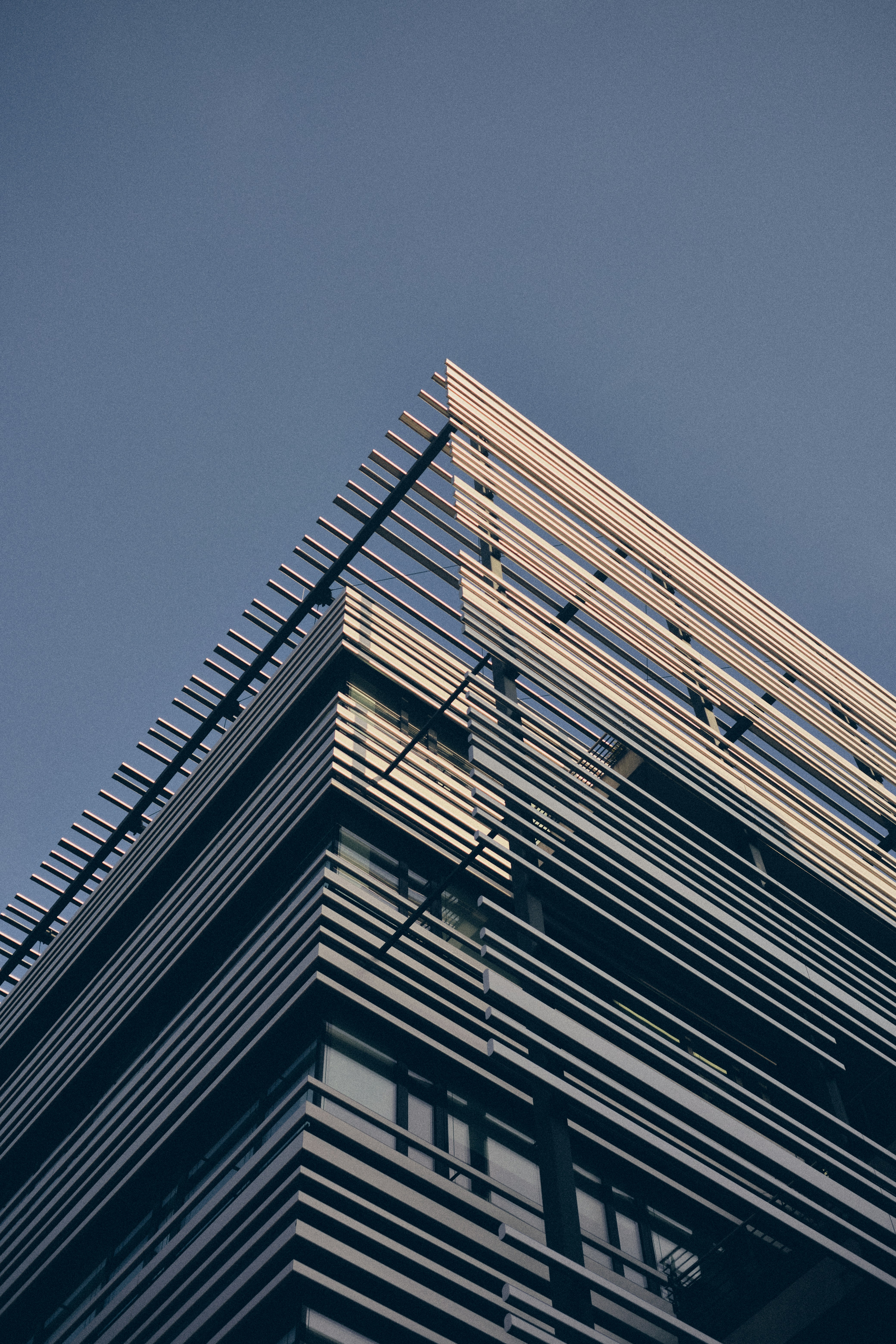 Skewed Facade: Striated Architectural Lines against a Clear Sky