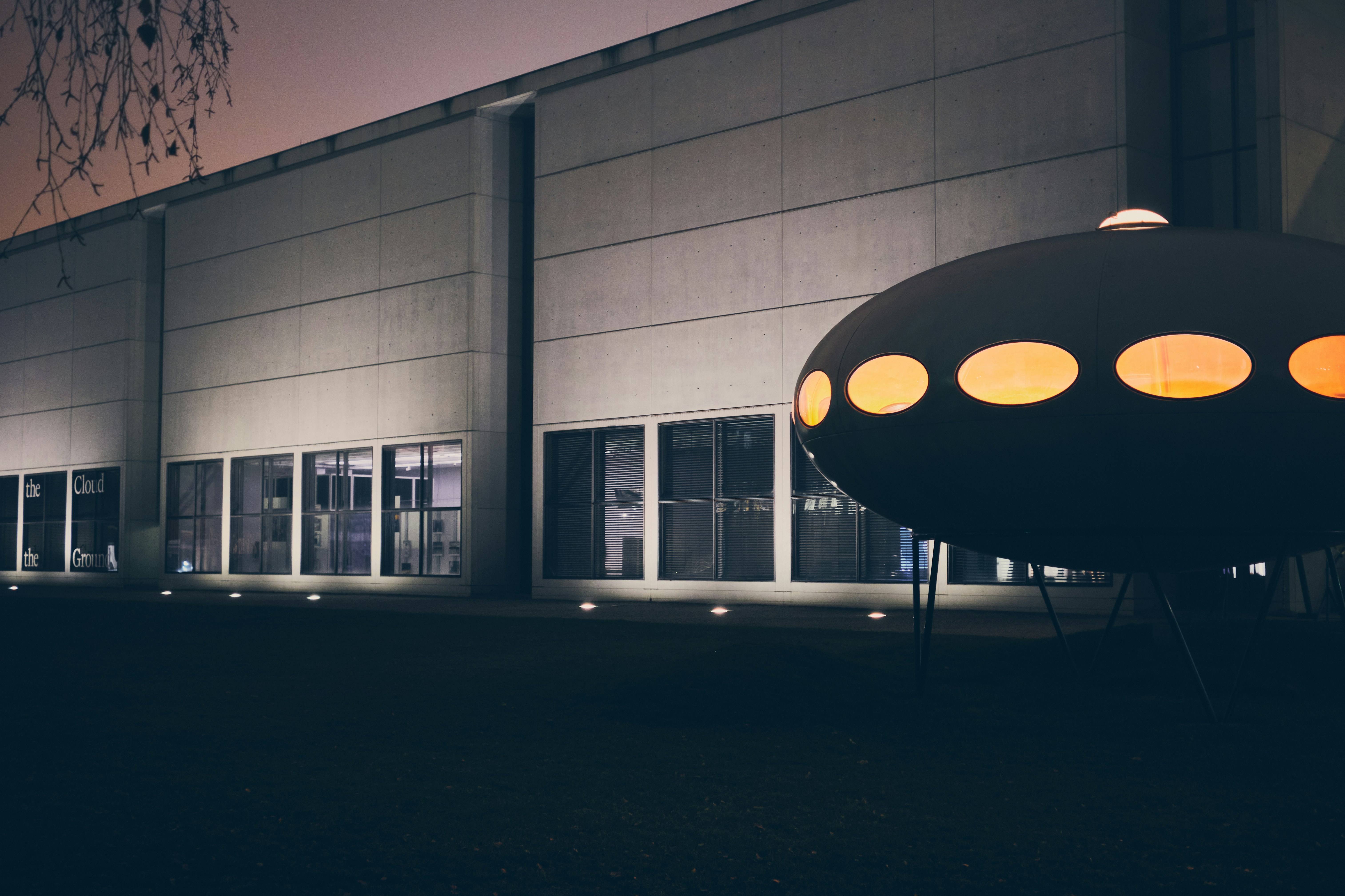 Futuristic mushroom-shaped building with glowing windows at night.