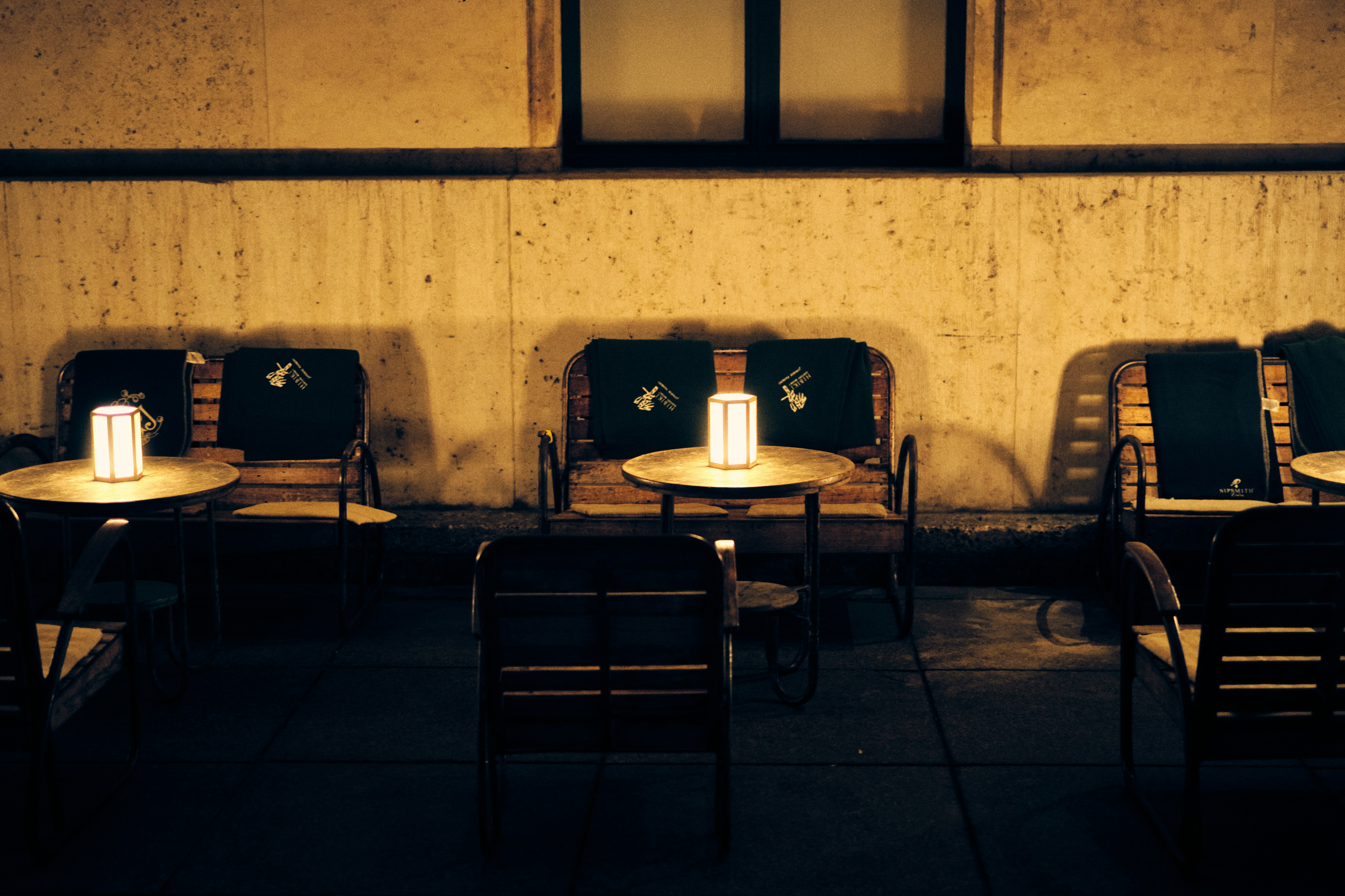 Outdoor cafe seating area at night with glowing table lamps.