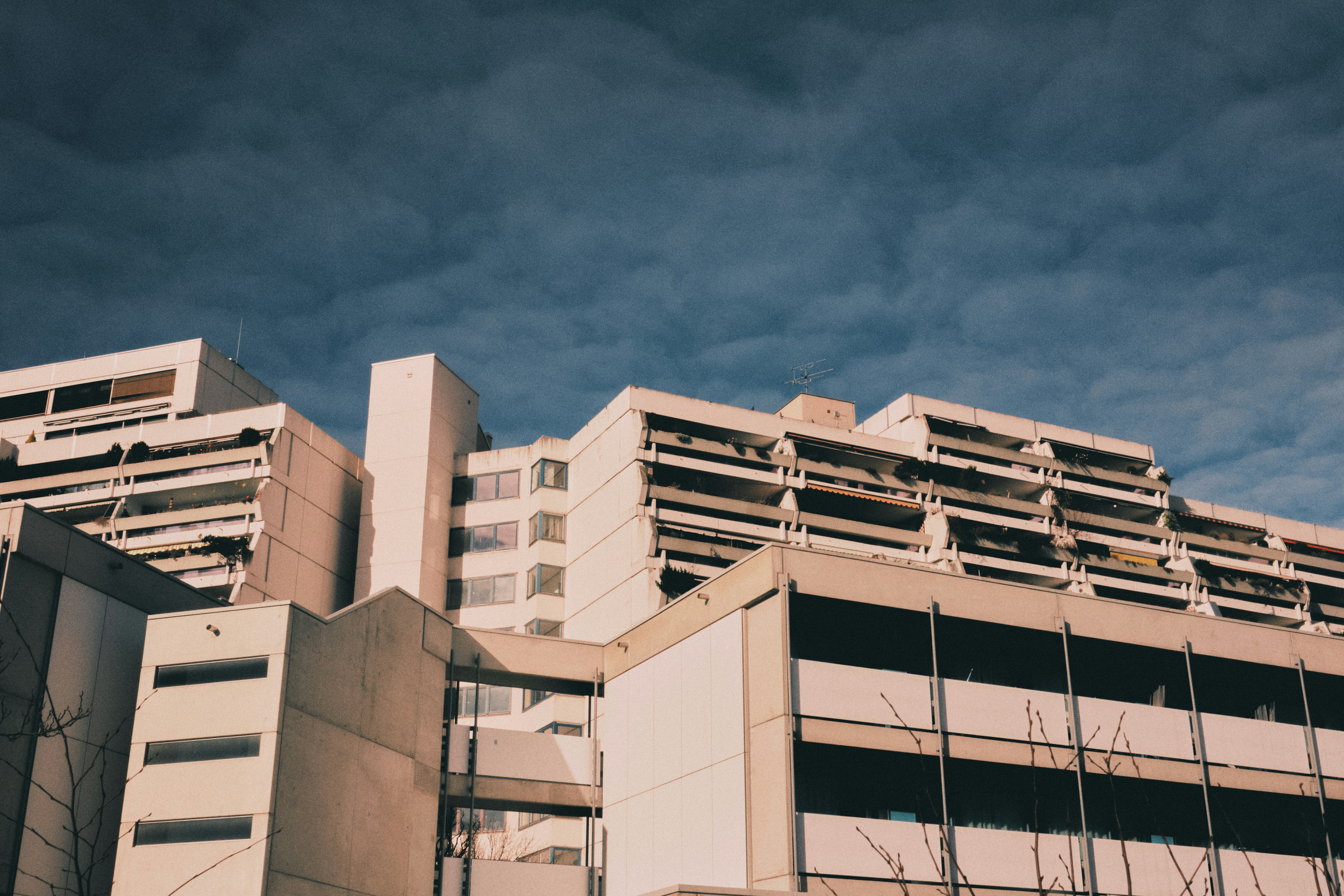 Multi-story building complex with balconies against a cloudy sky.