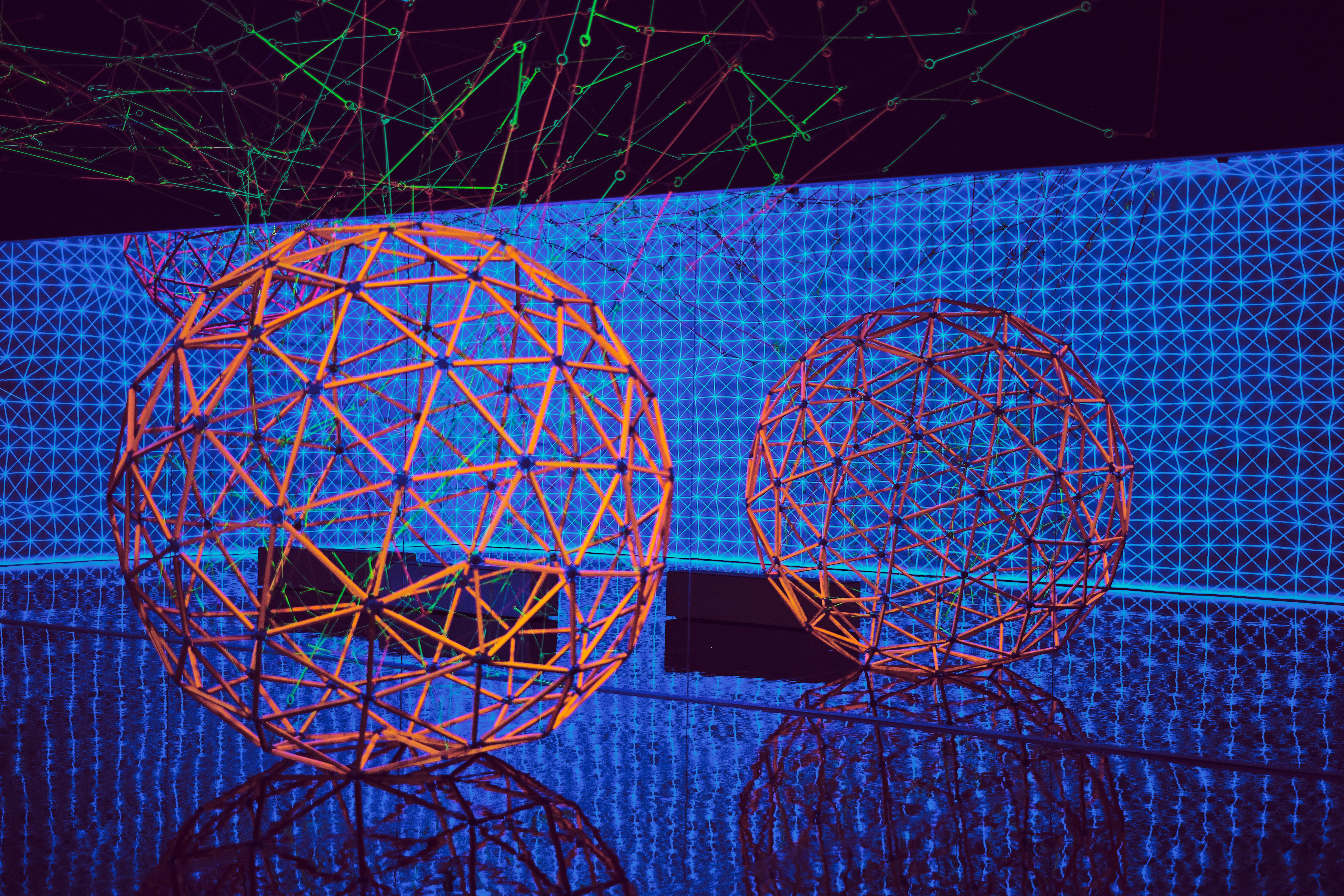 Orange wireframe spheres reflected on a blue patterned surface.