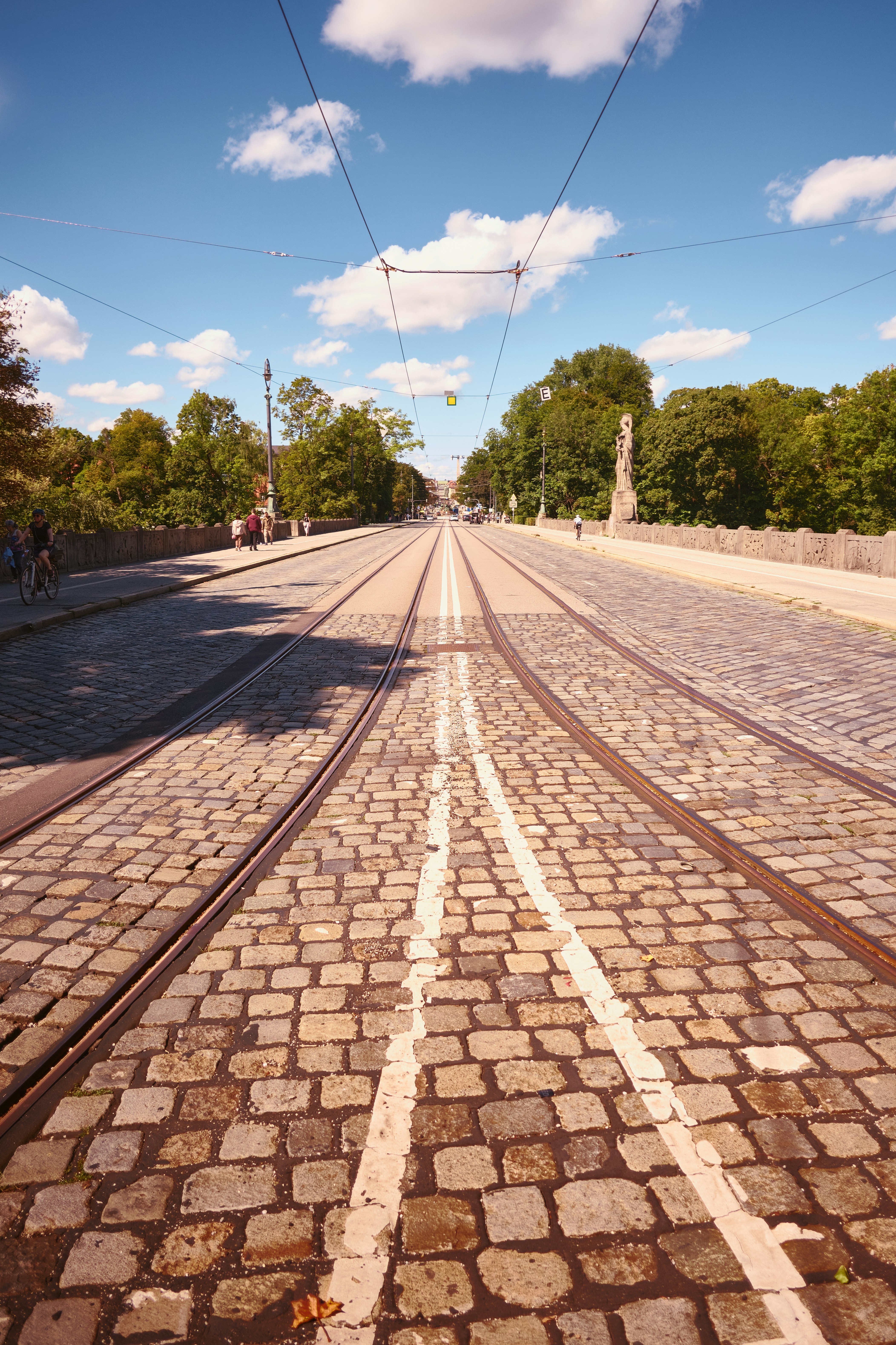 Tracks to the Horizon: A Cobbled City Crossing under Wide Sky