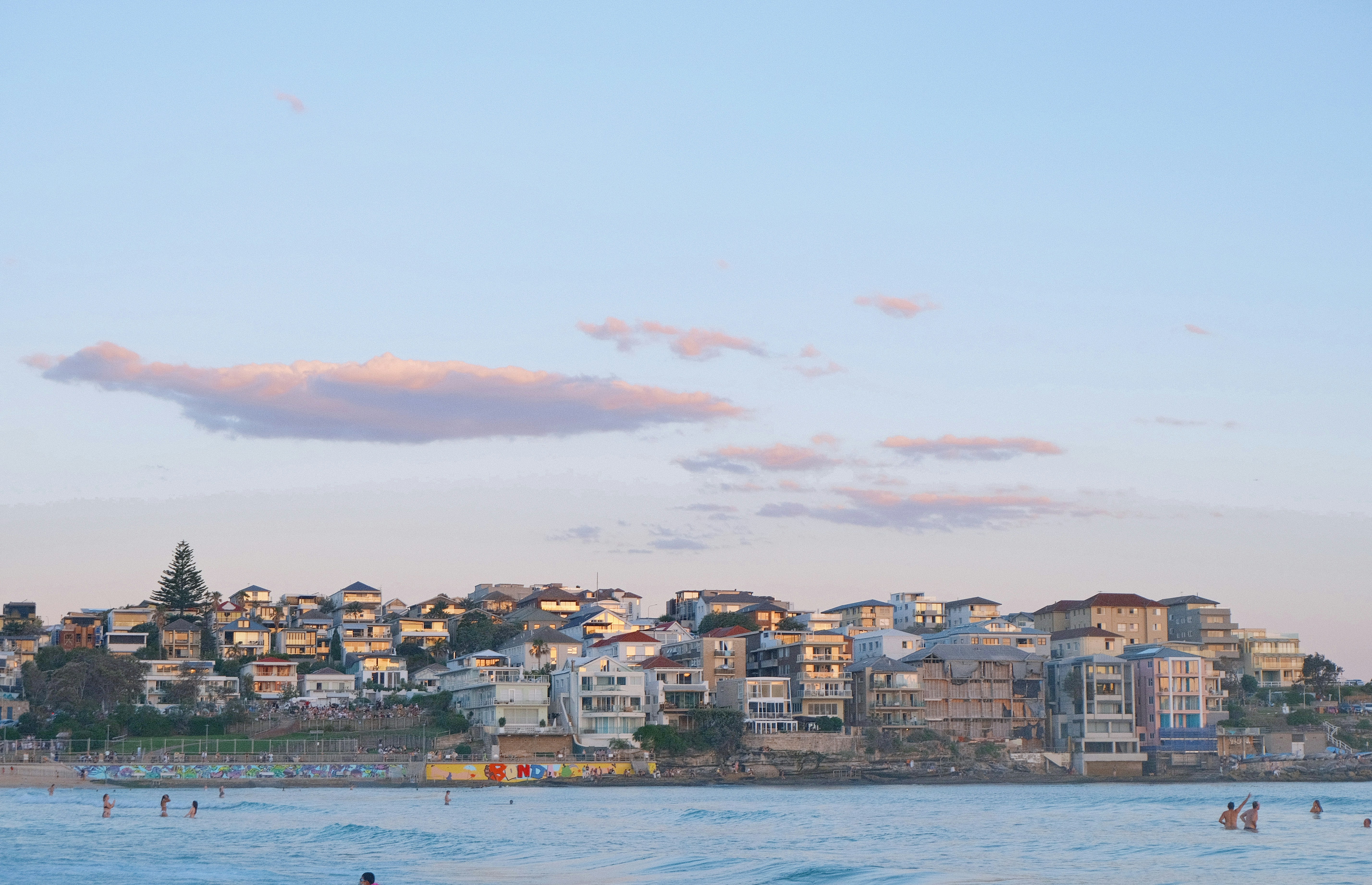 Coastal hillside village alight with pastel dusk over calm sea