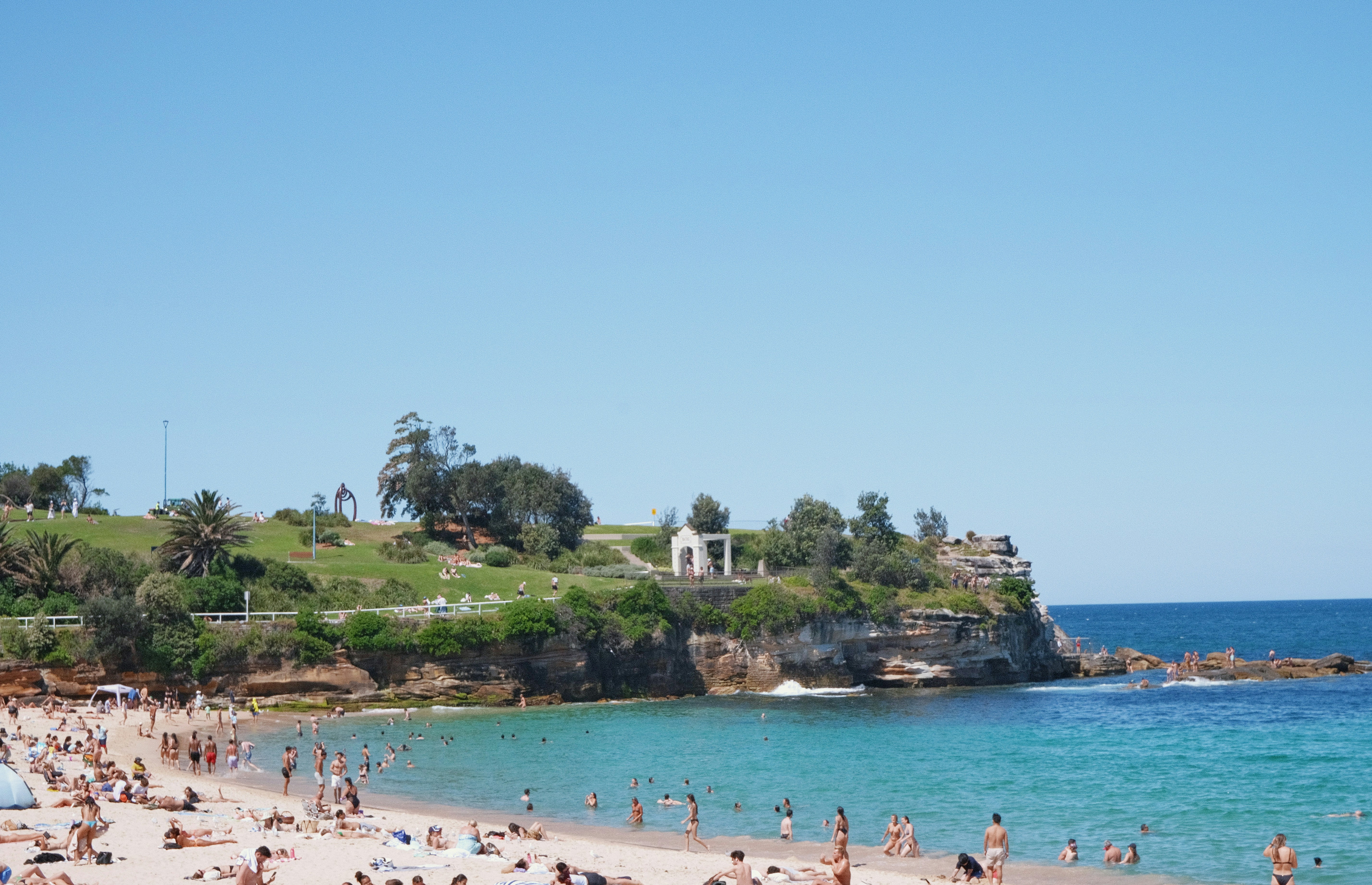 Cliffside Coastline with Sunlit Beachgoers