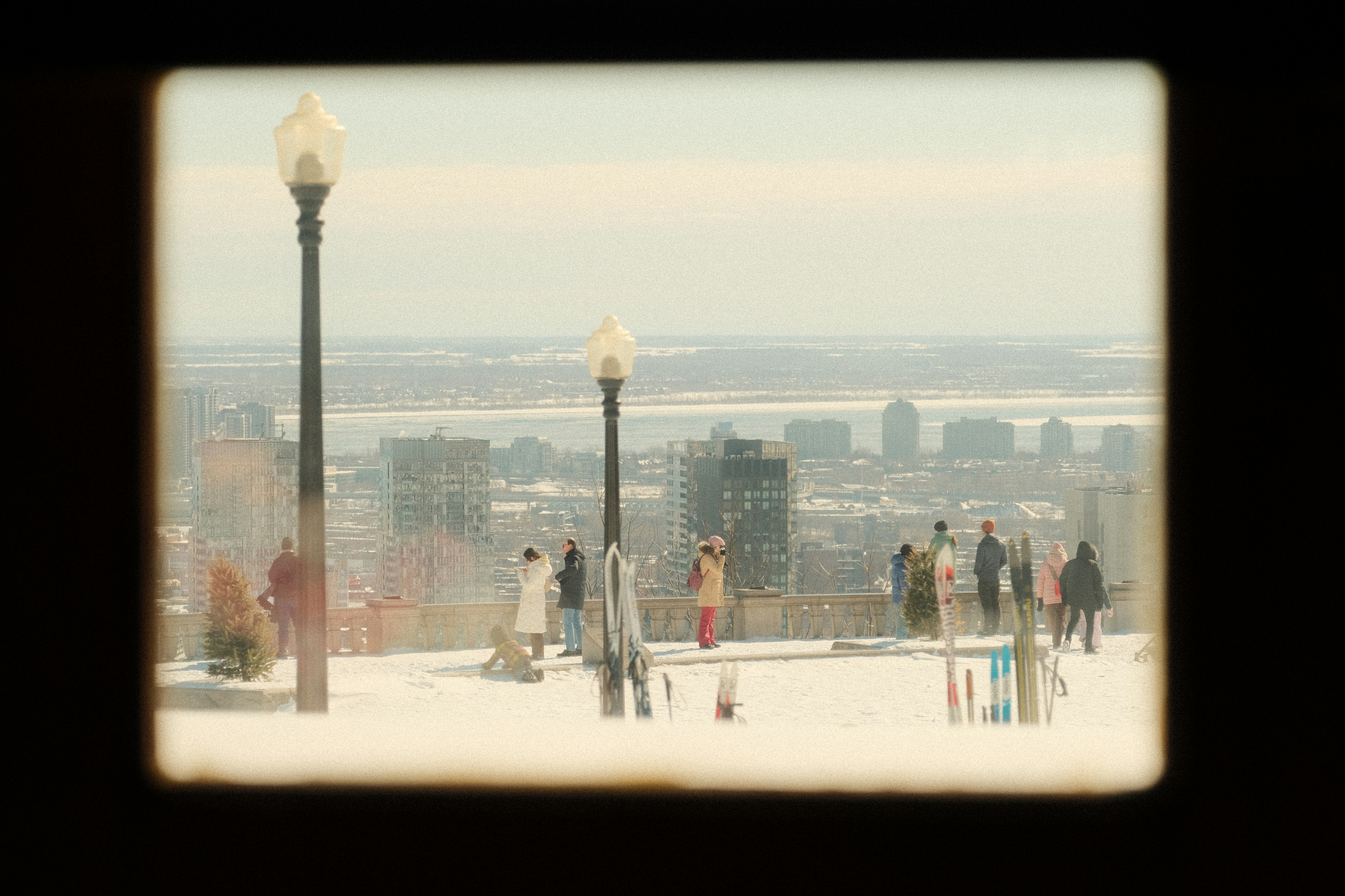Snowy terrace at dusk: city silhouettes beneath vintage streetlamps