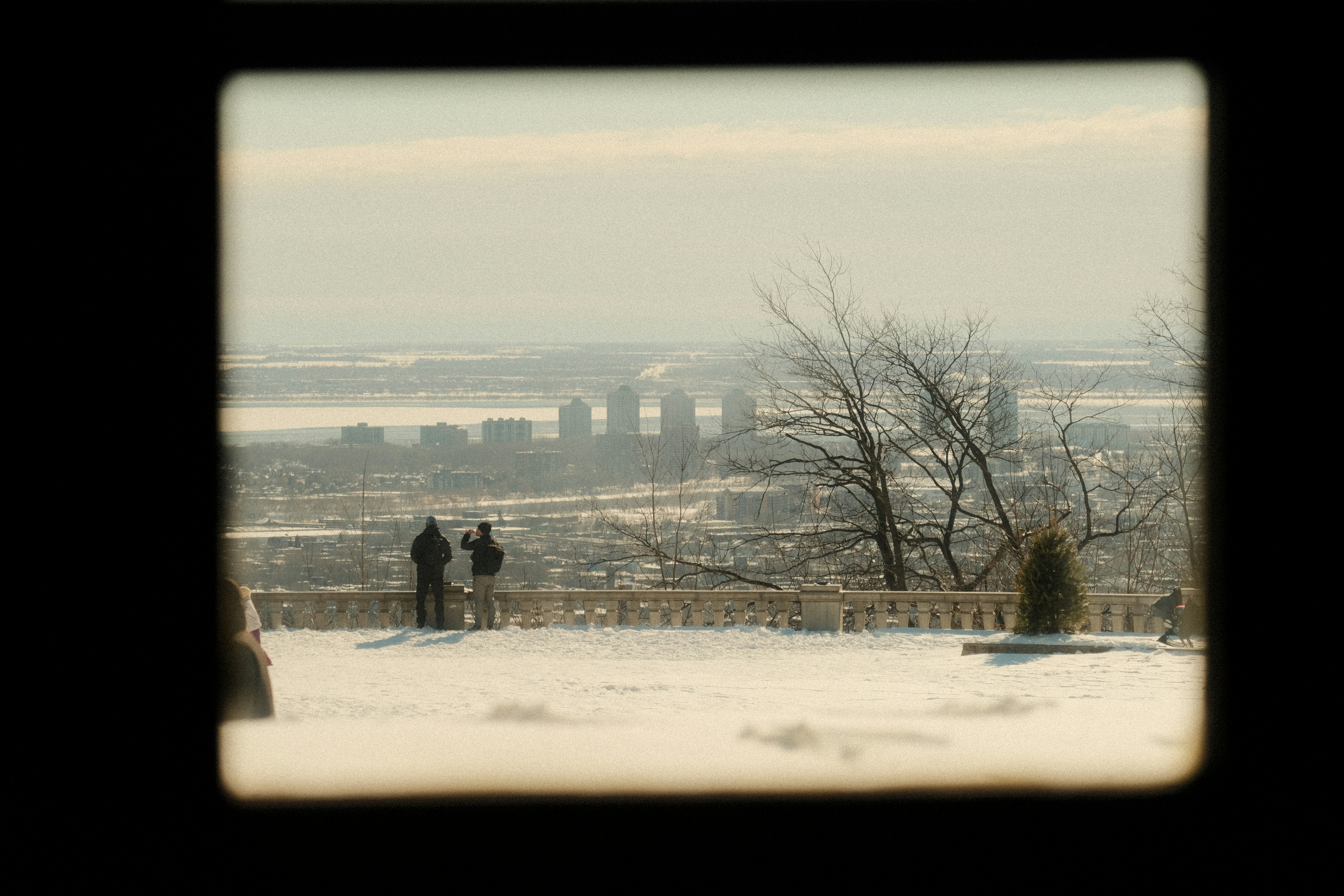 Snowy overlook: silhouettes against a distant city horizon