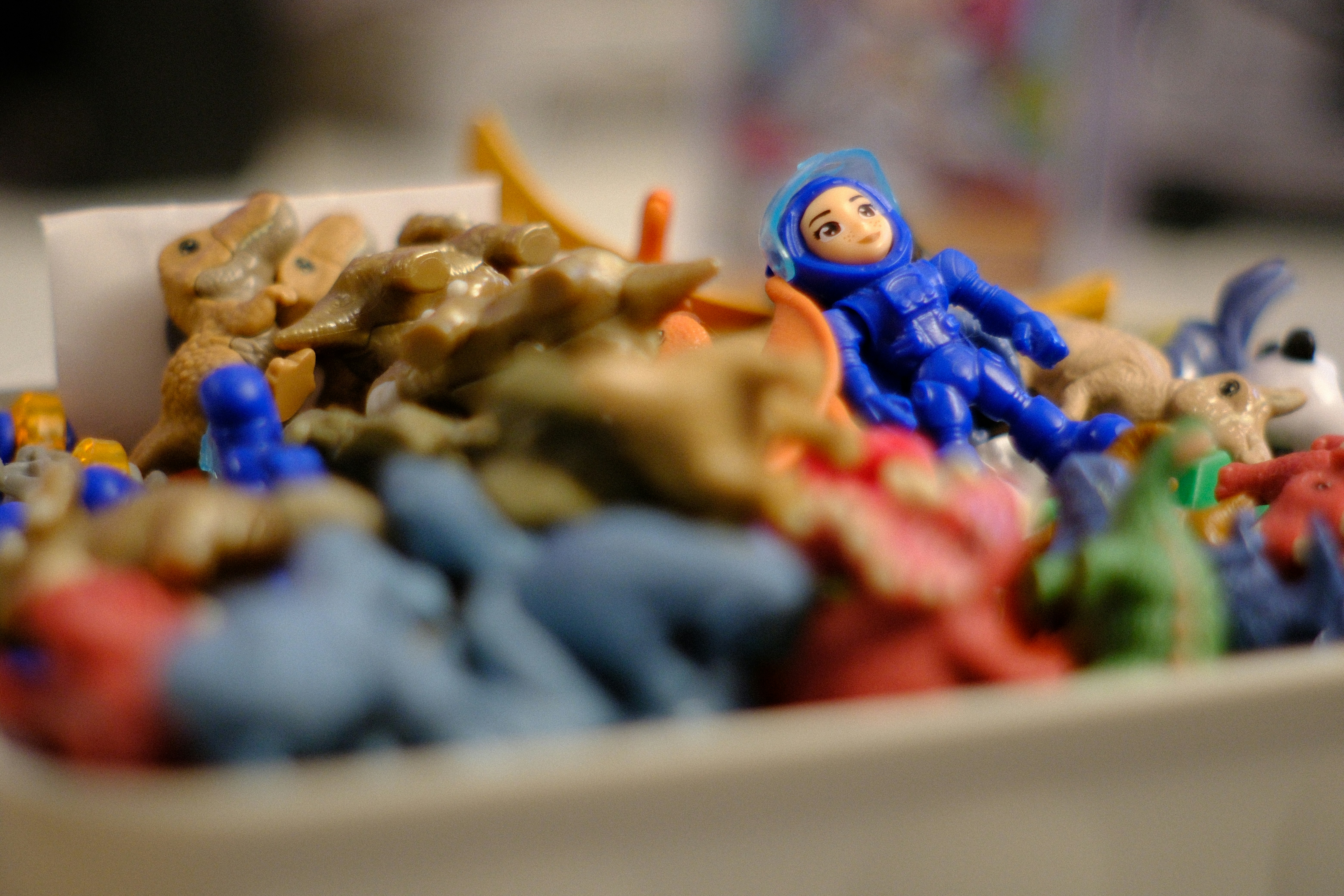 Tiny Blue Astronaut Among the Busy Toy Swarm