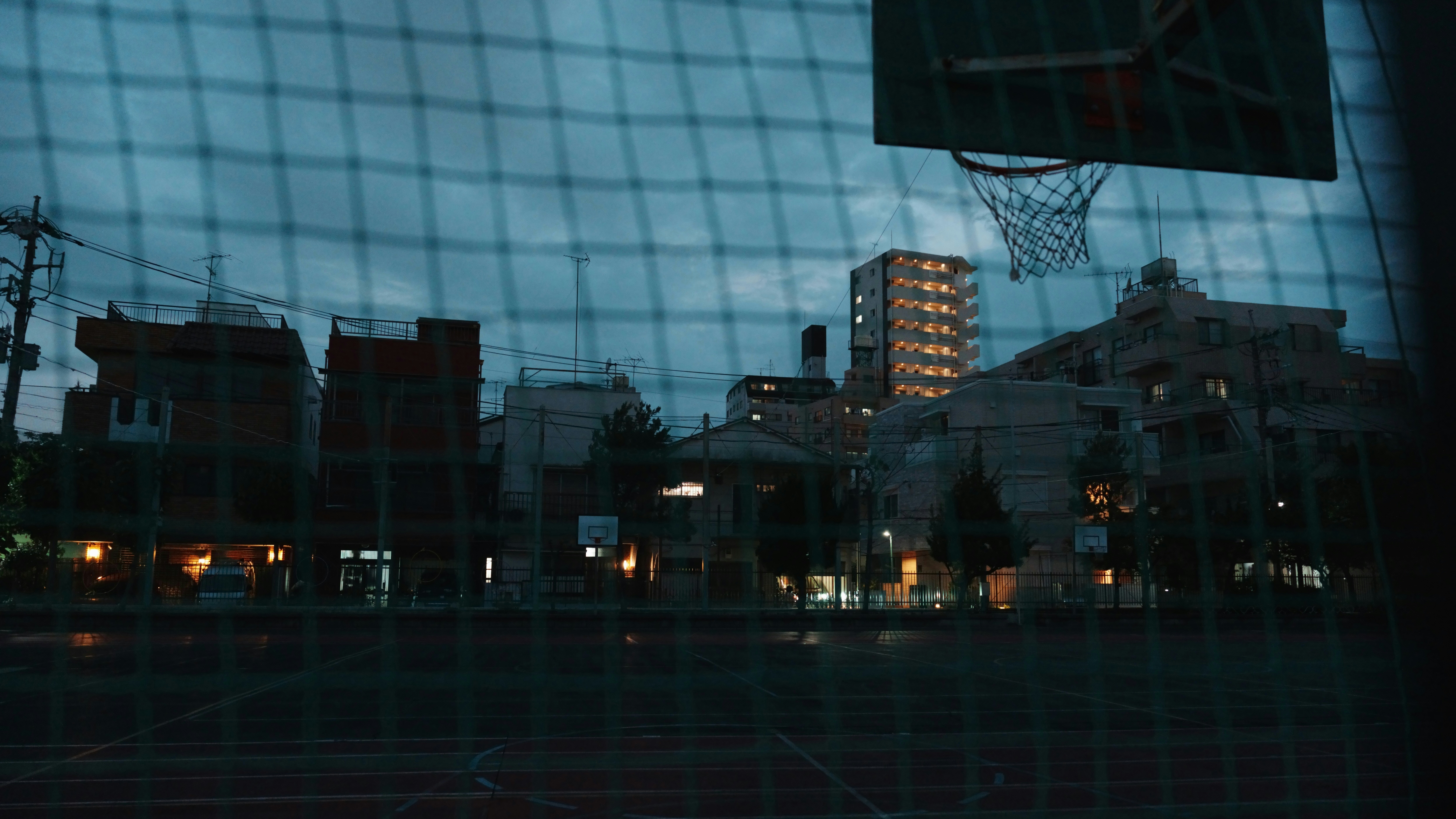 Netted Court at Dusk: City Lights Beneath a Bassline of Netting