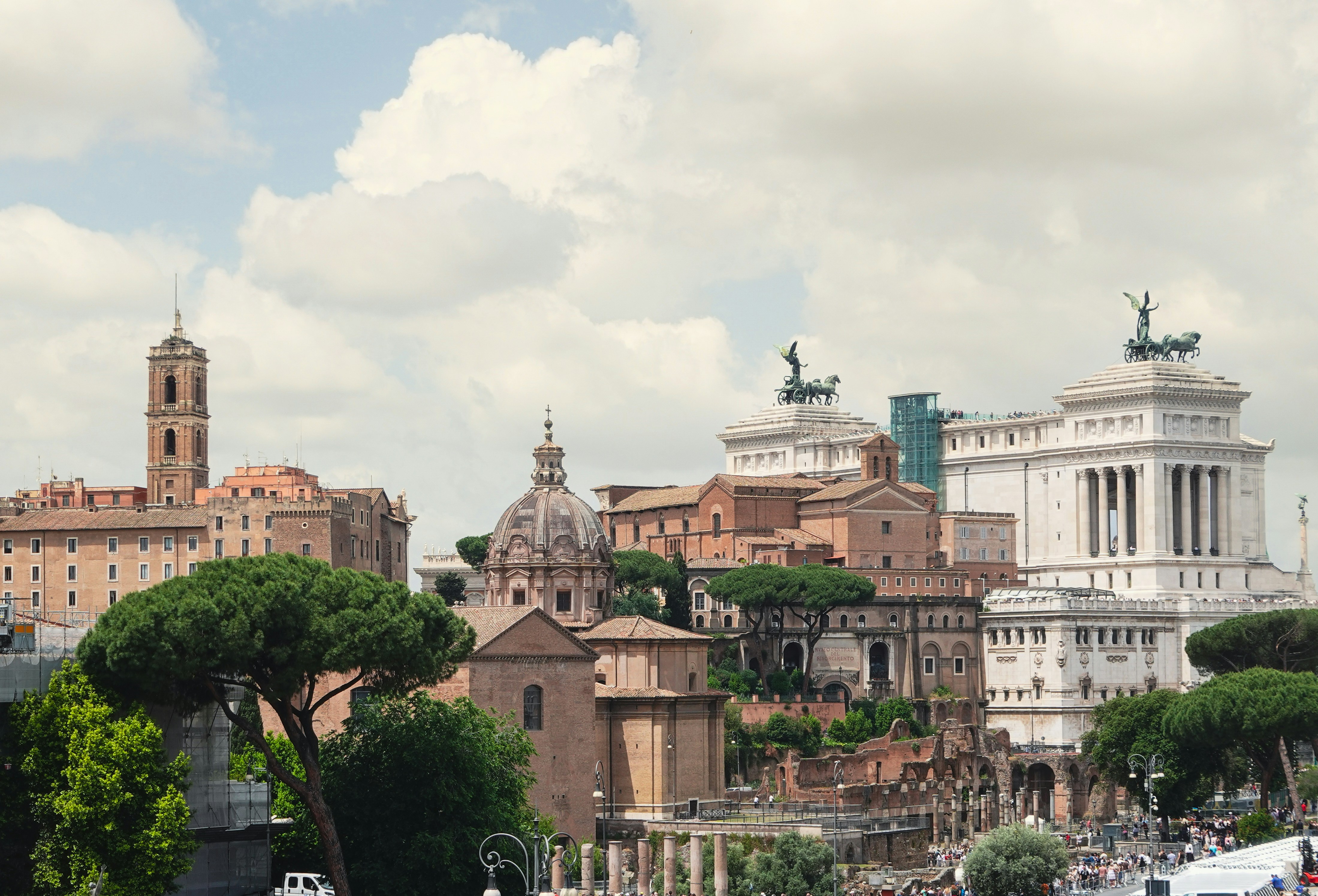Rome's Classical Horizon: The Colossal White Structure Framed by Verdant Street Trees