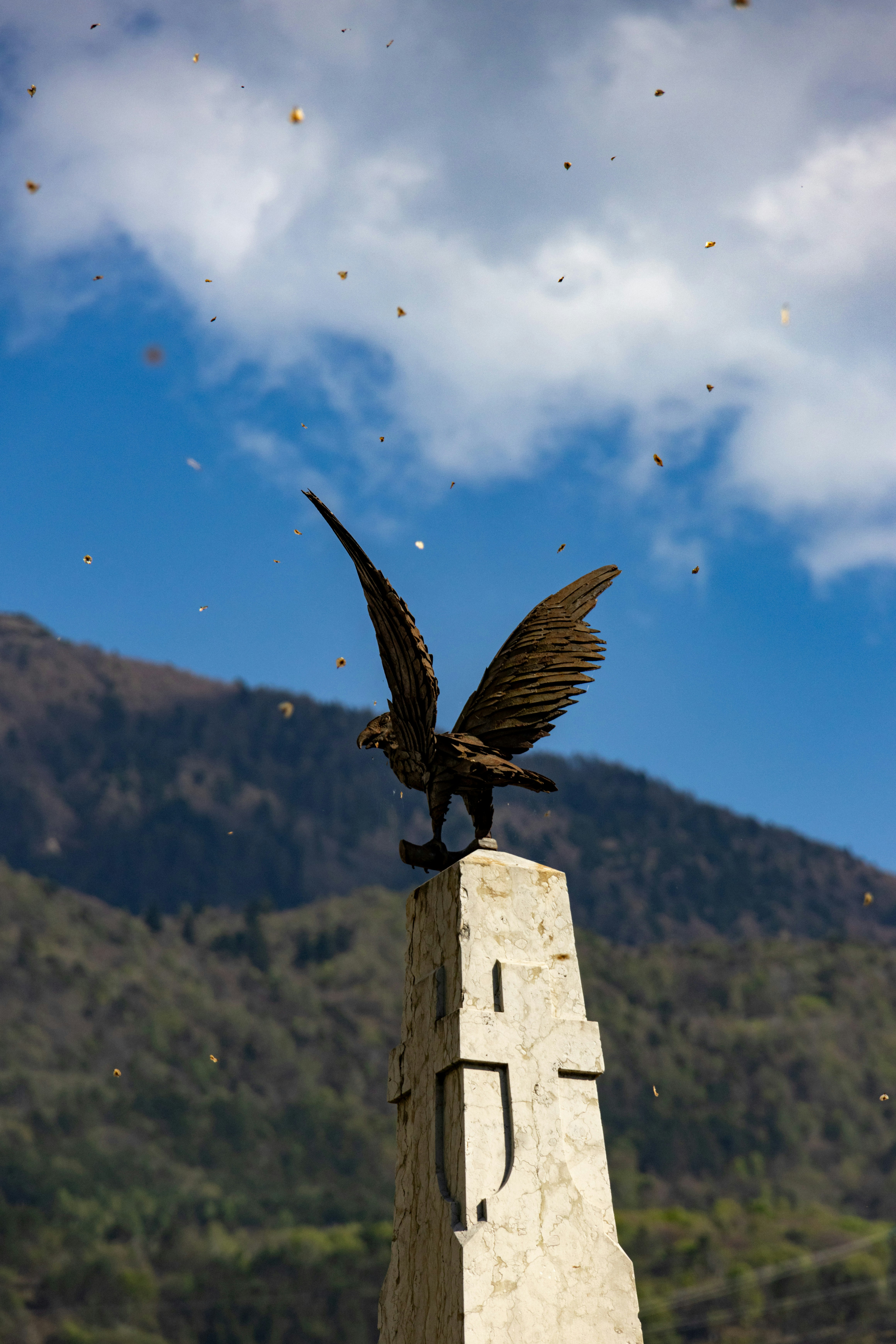 Bronze eagle sculpture on a war memorial with mountains and blue sky in Villazzano, Trento, Italy