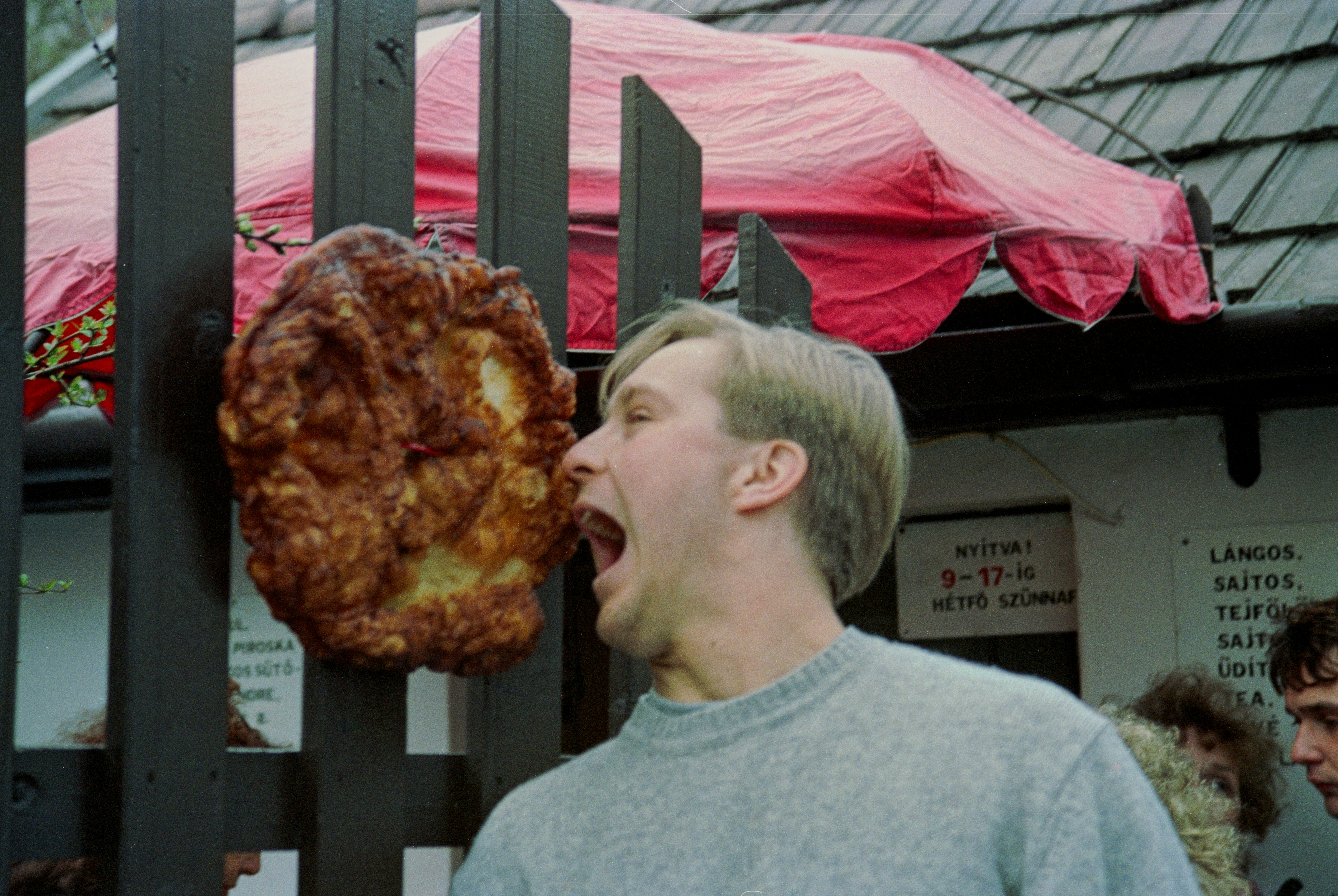 Toast of the Carnival: A Man Bites into a Hanging Pastry
