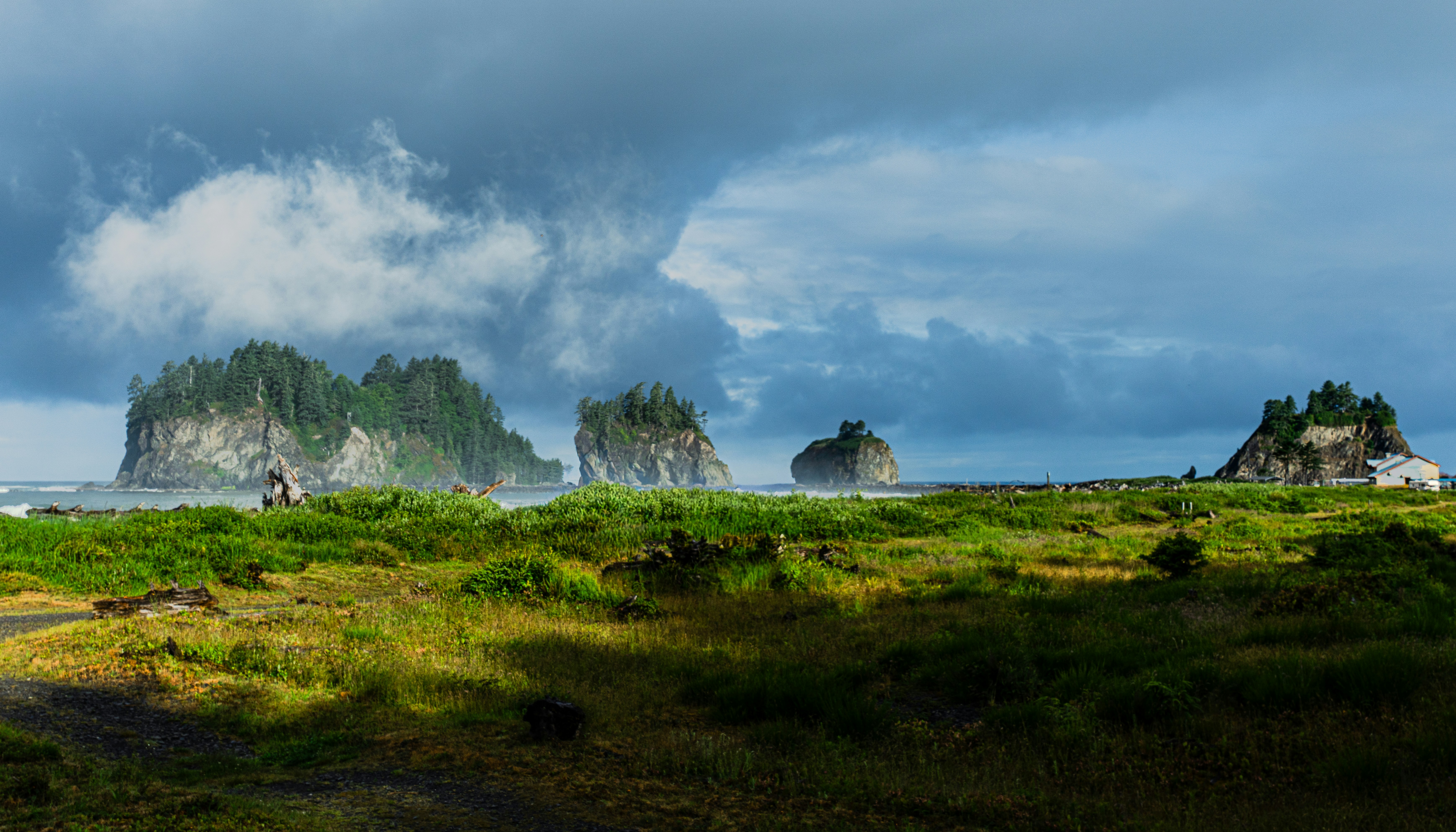 Dramatic cloudy sky over sea stacks and green land.