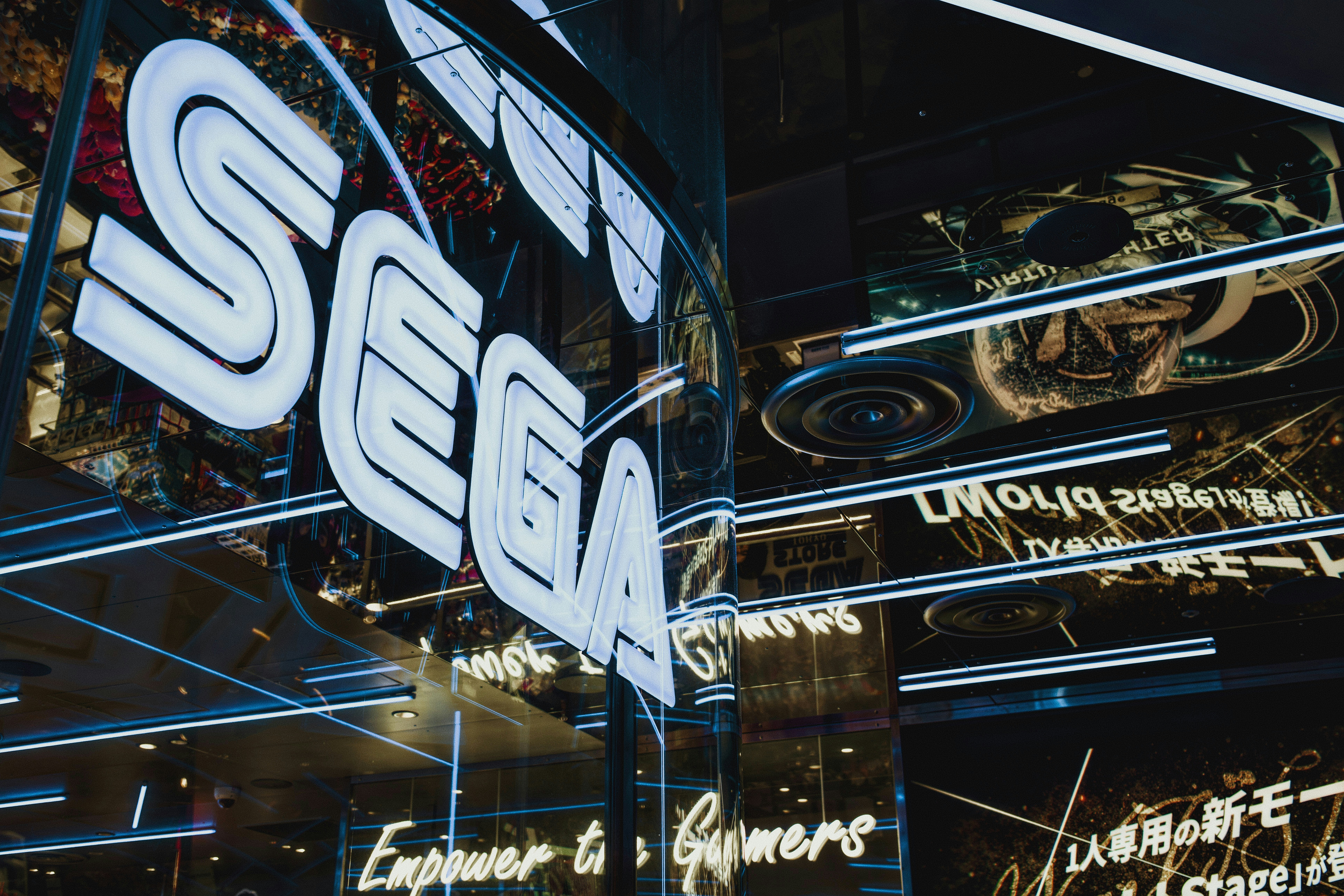 A neon sega sign reflected on a dark, glossy surface.