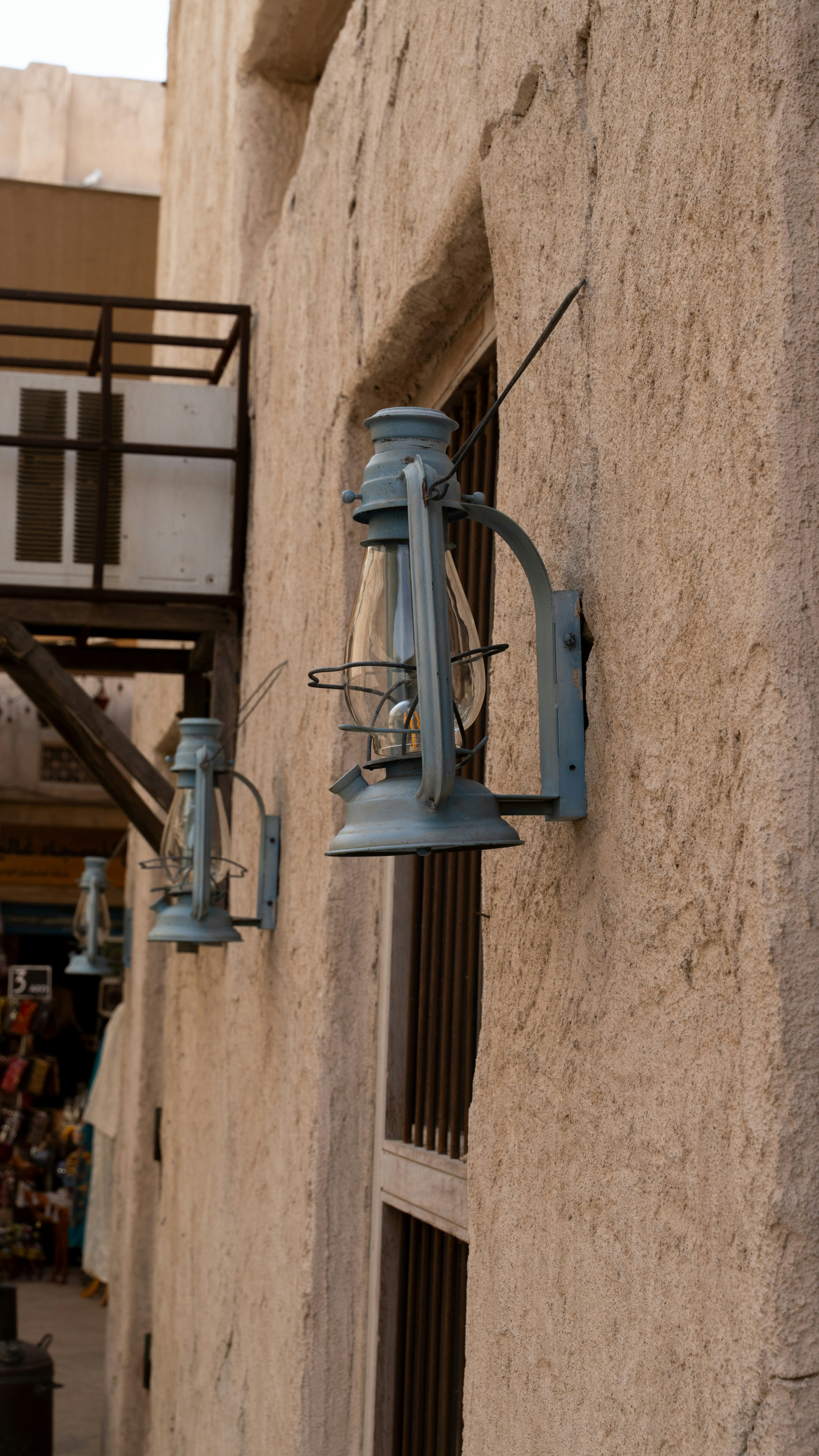 Blue Lanterns Line the Sunlit Facade of a Deserted Alley