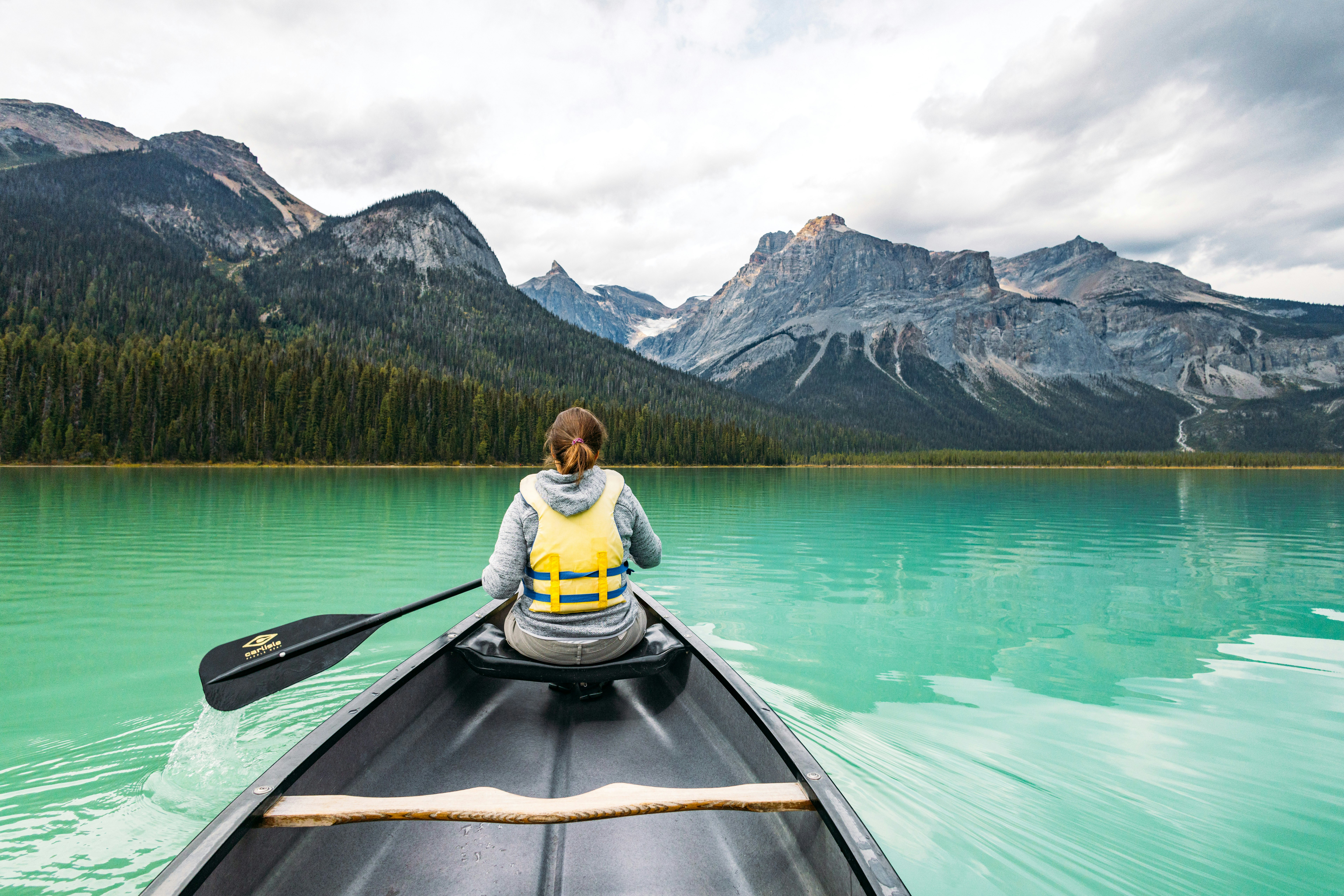 Venture toward the emerald lake: a lone paddler in a canyon-quiet moment