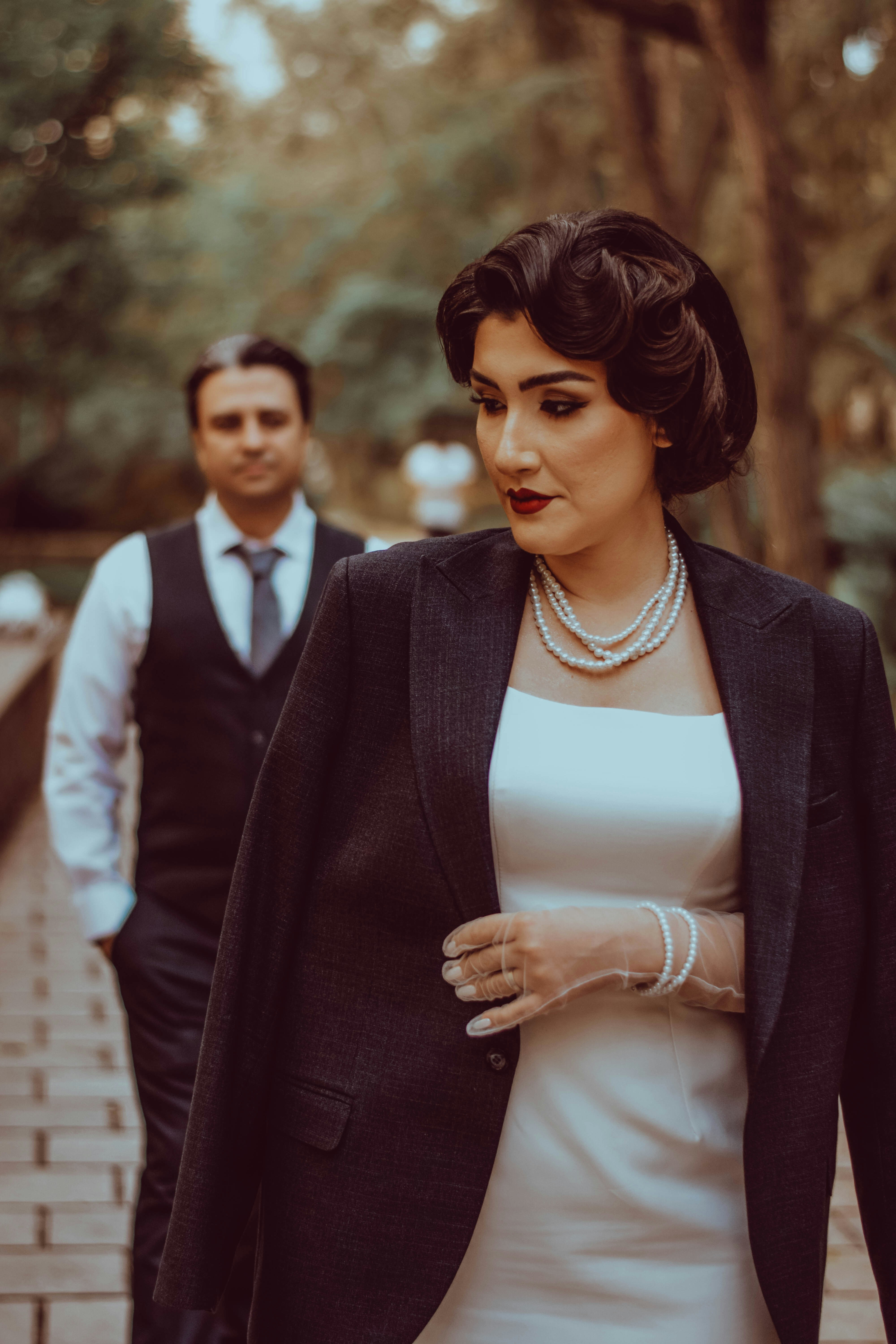 Elegance in Focus: A Woman in a Pearled Moment with a Shadowed Suitor