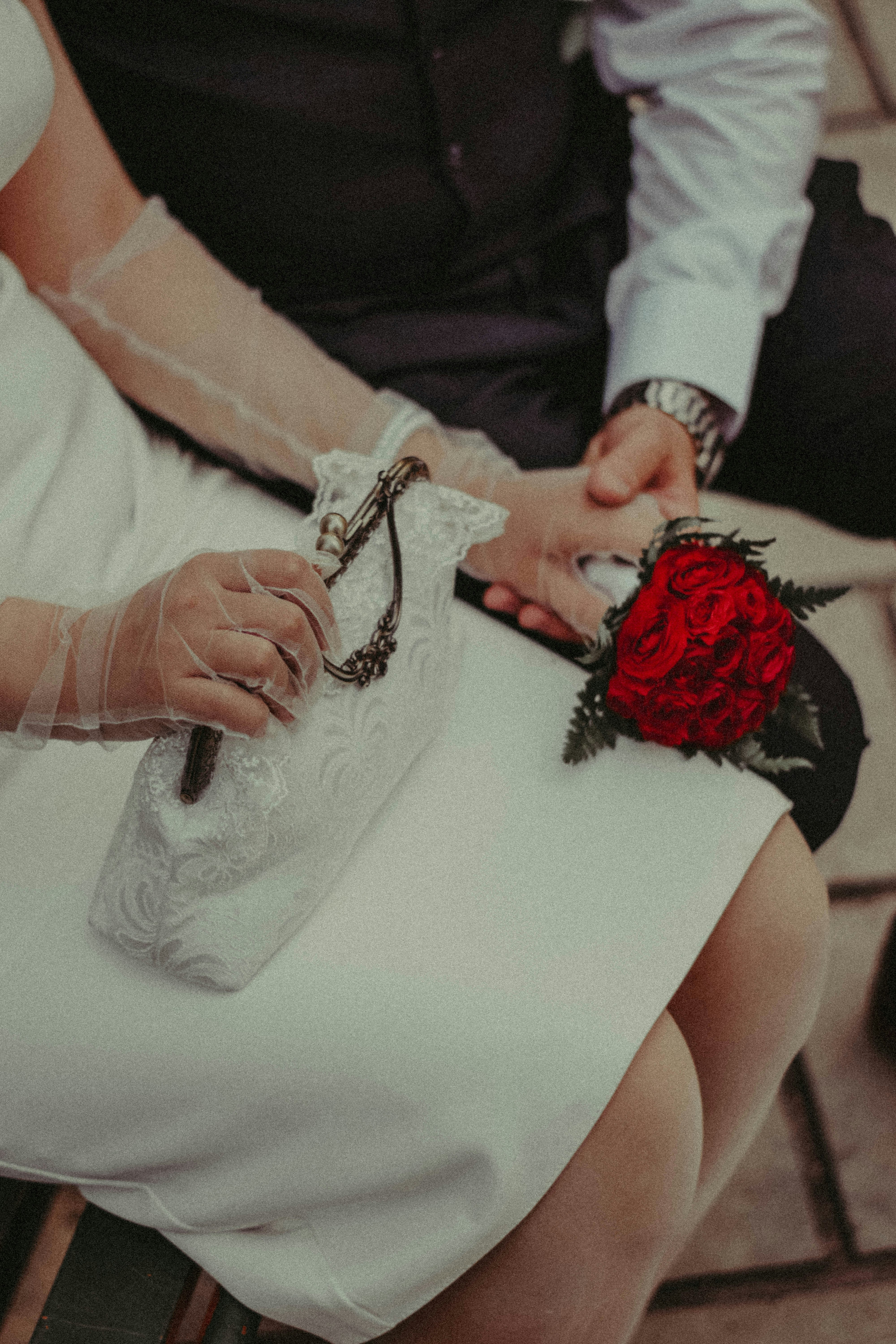 A Quiet Moment: Bride’s Gloved Hands Resting Near a Red Rose Boutonniere