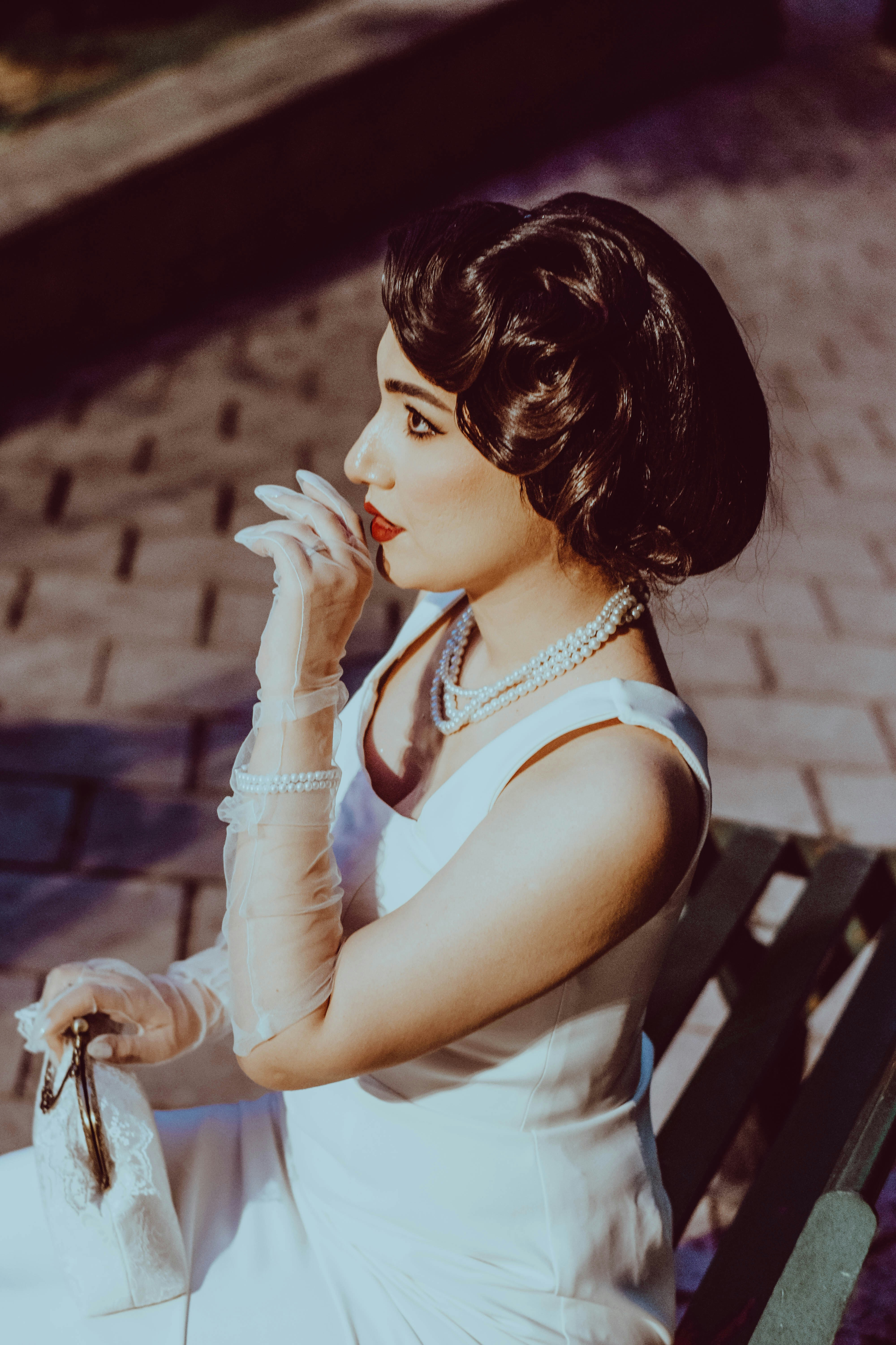 Vintage glamour on a sunlit bench: a poised ingénue in pearls