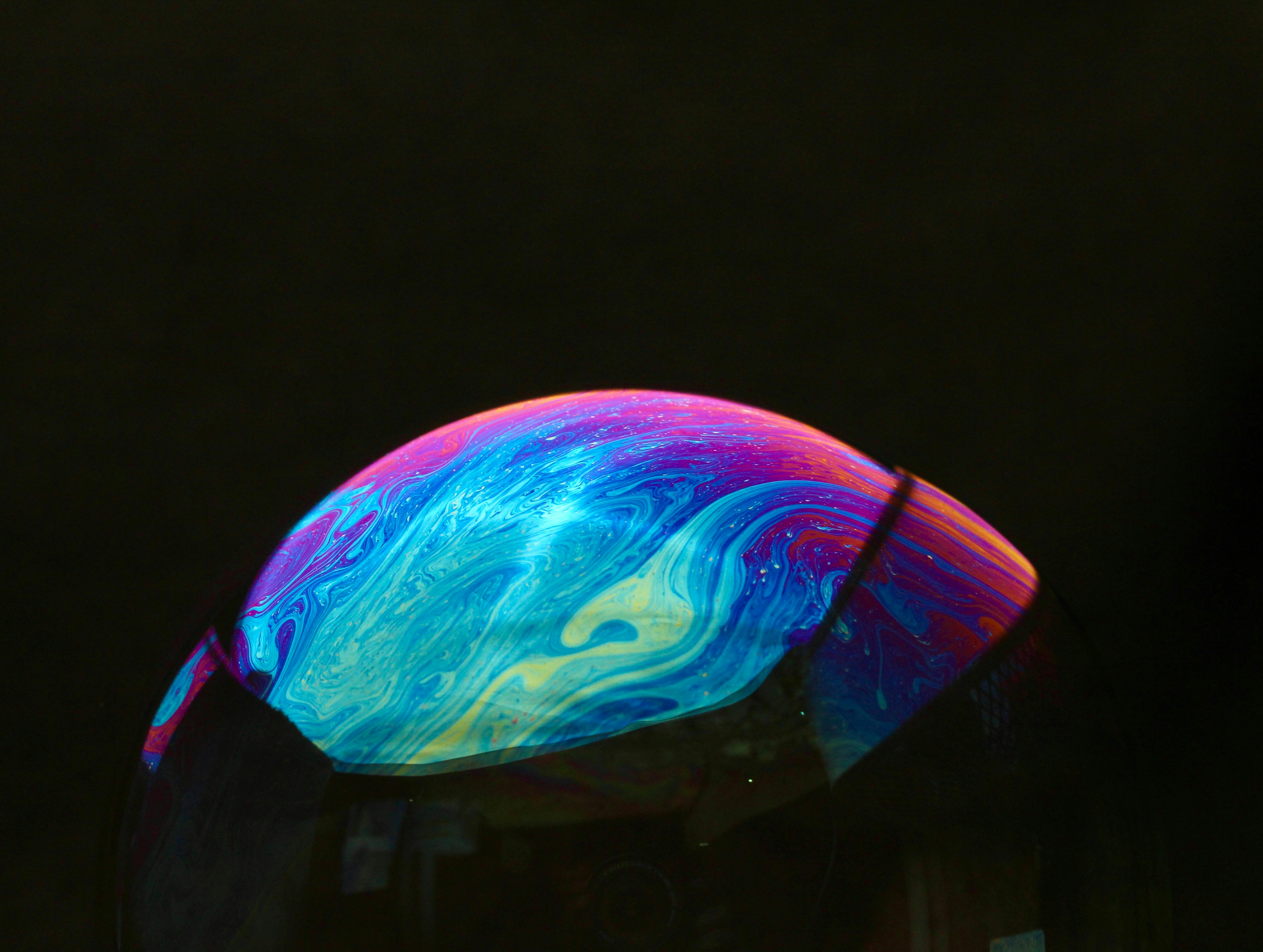 Aurora Pearl: a vibrant soap bubble resting on a dark plane