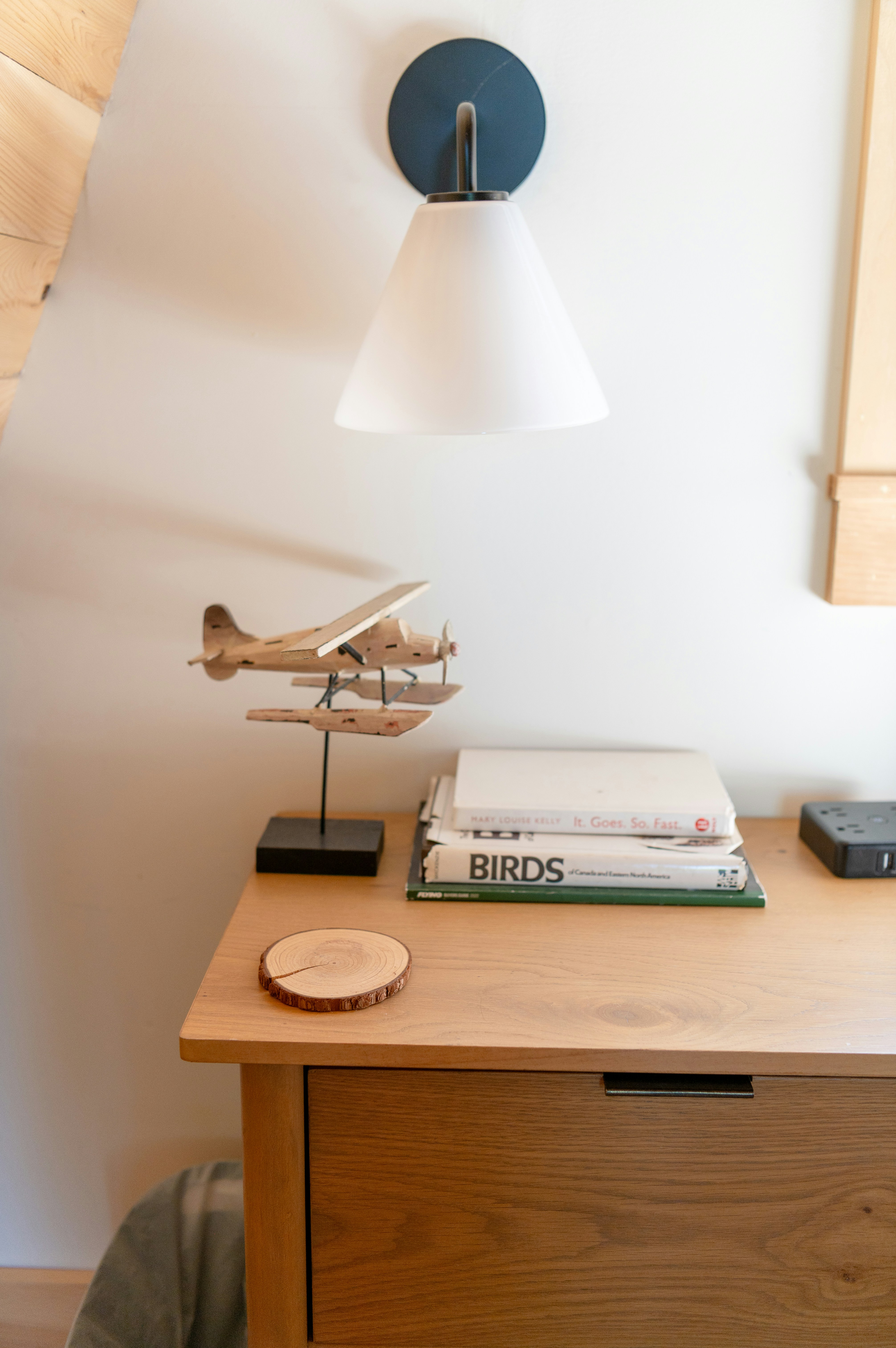 Wooden model airplane and books on a nightstand.
