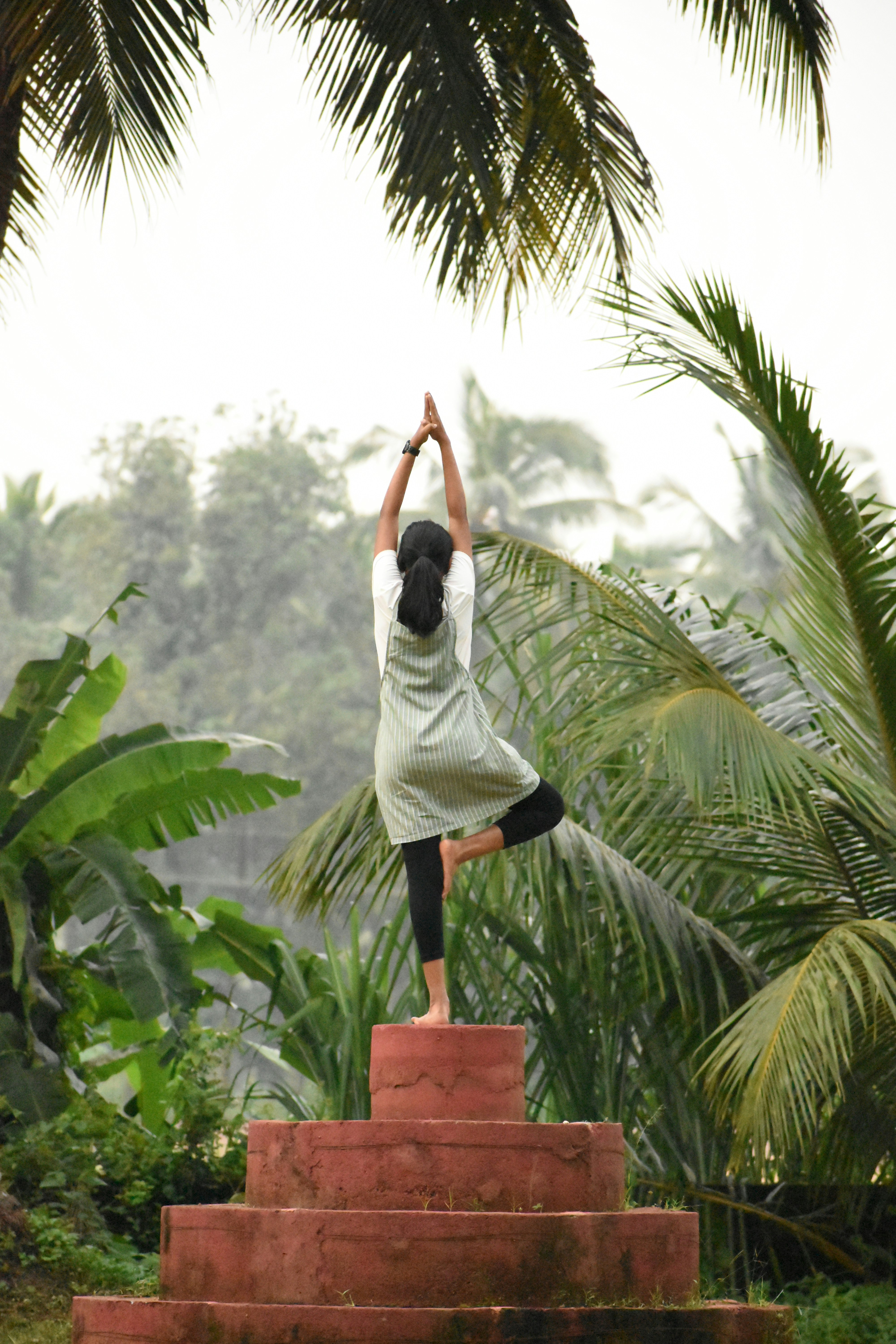 Yoga Above the Terrace: Woman on Brick Steps in a Lush Tropical Garden