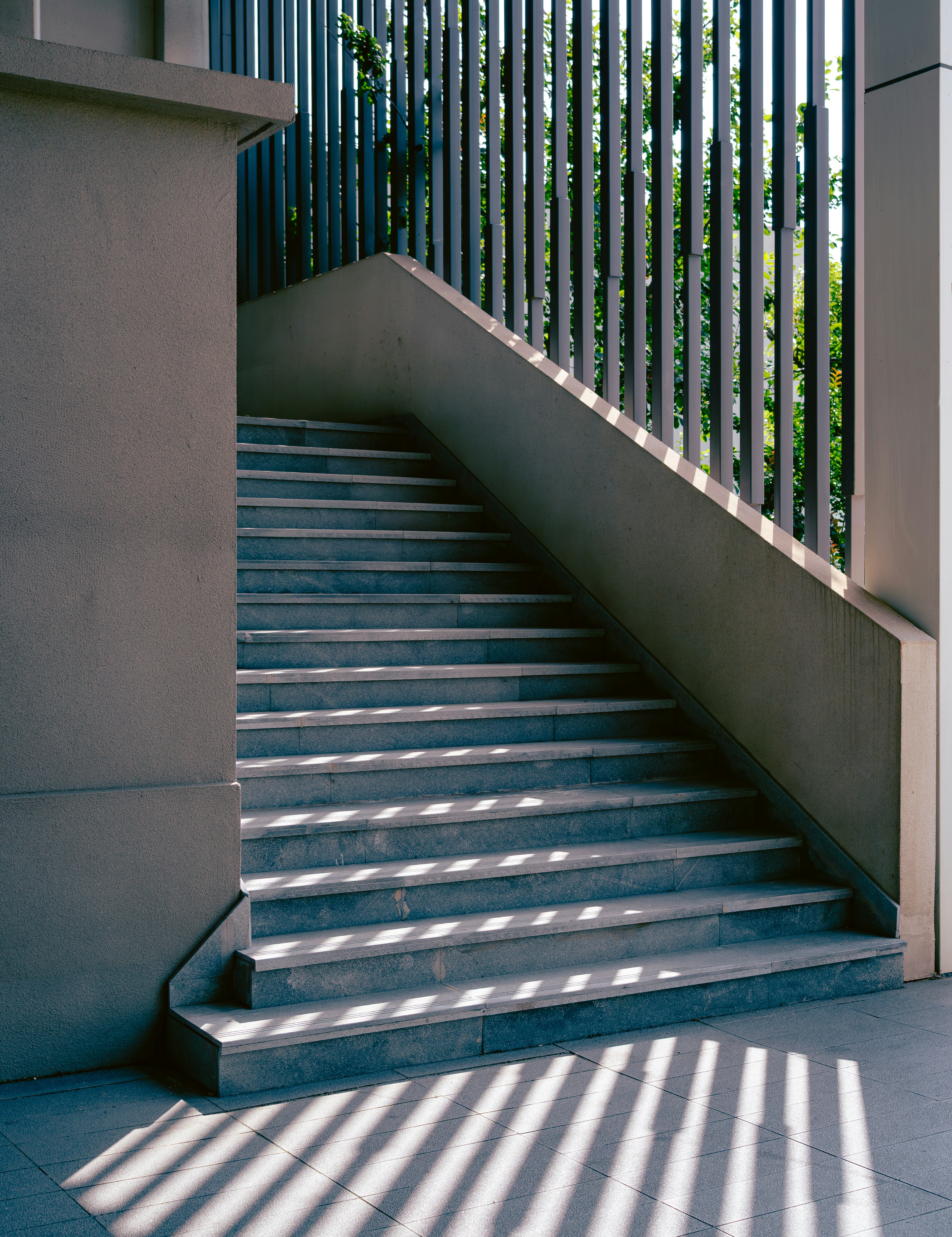 Concrete stairs with striped shadows from a railing.