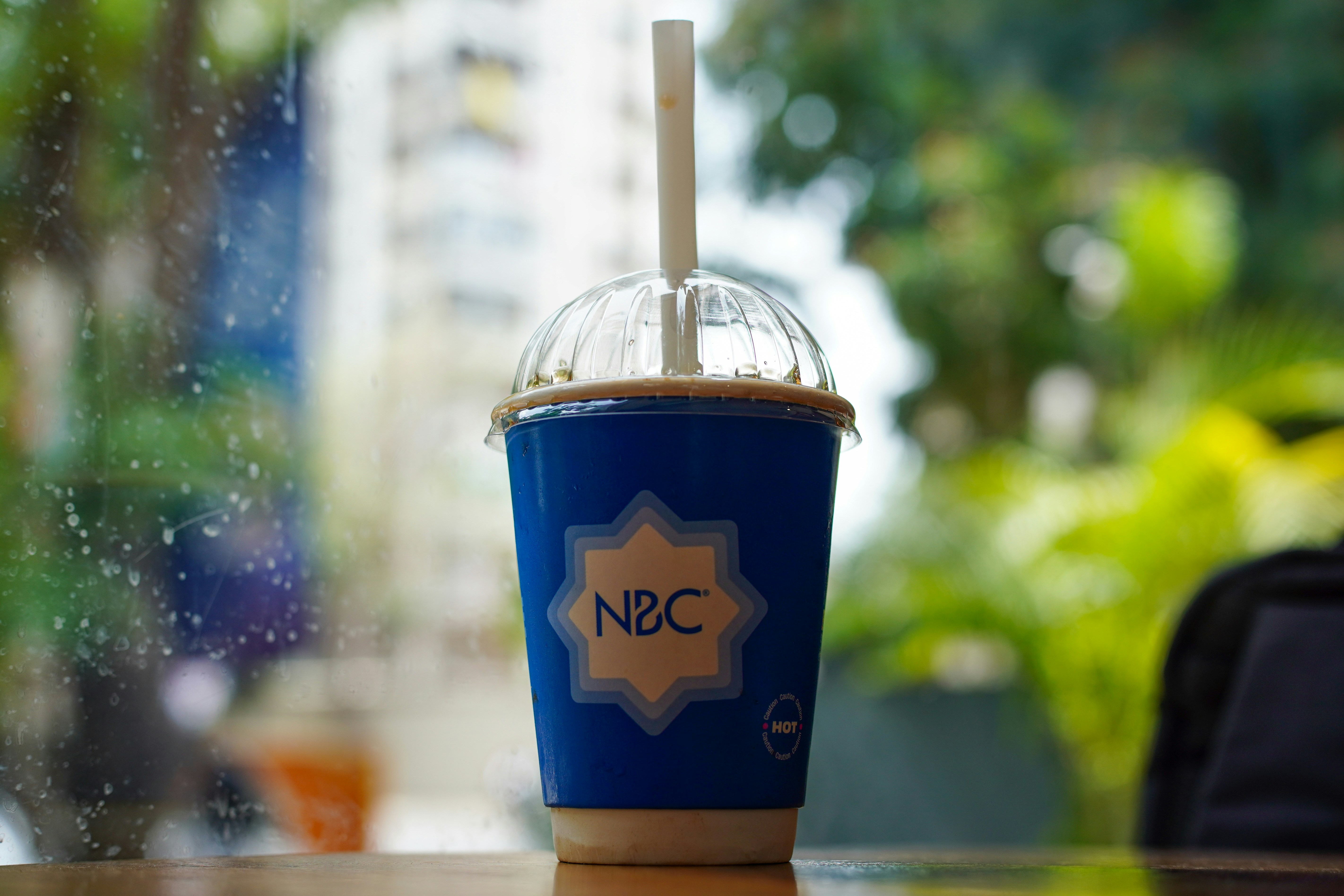 Starburst Cup in Focus: A Blue Logo Amid Blurred City Light