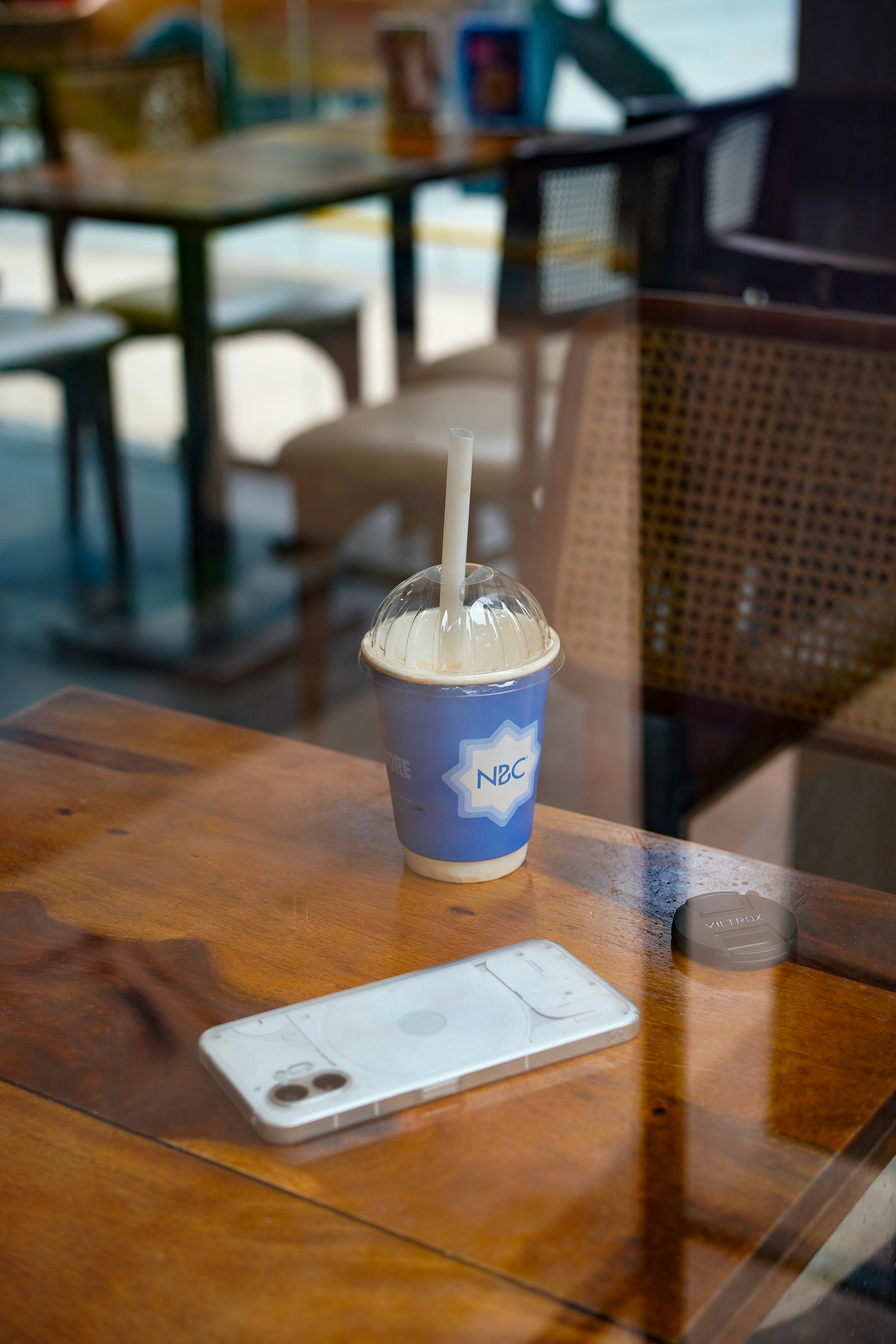 Midday Café Quiet: A Milkshake and Phone Rest on a Wooden Table