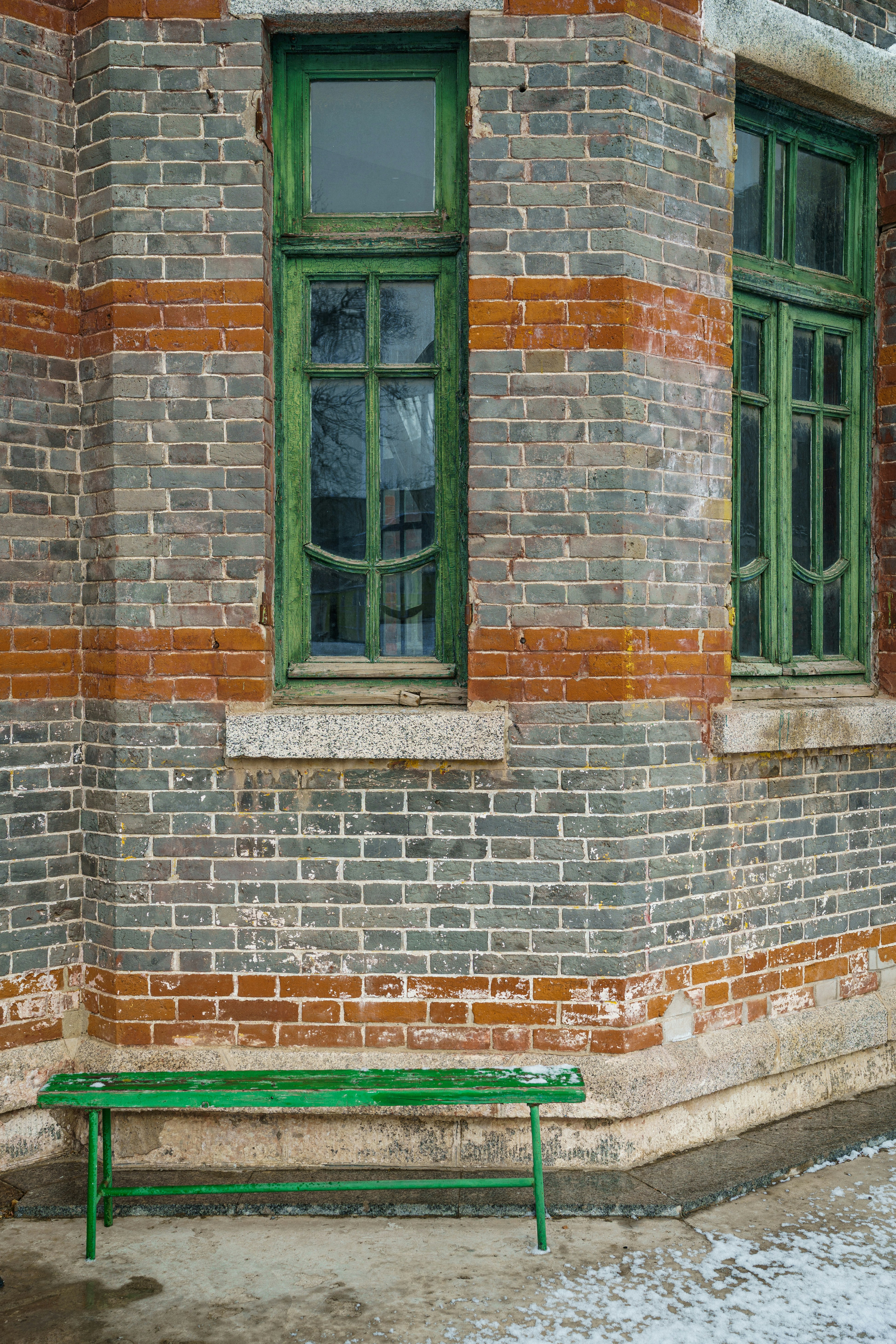 Green Windowed Facade and Lone Green Bench