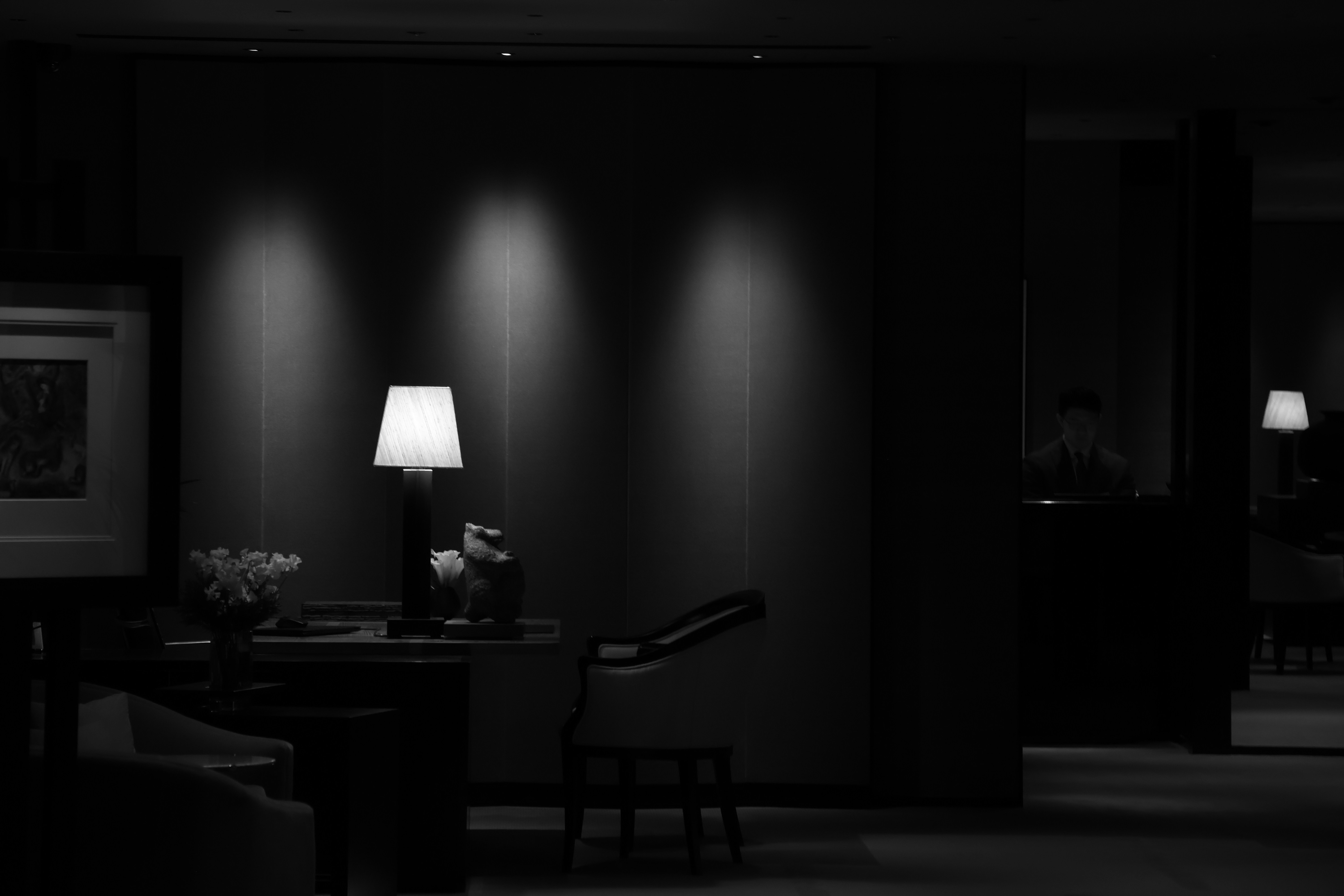 Dark interior featuring a lit table lamp and wall spotlights.
