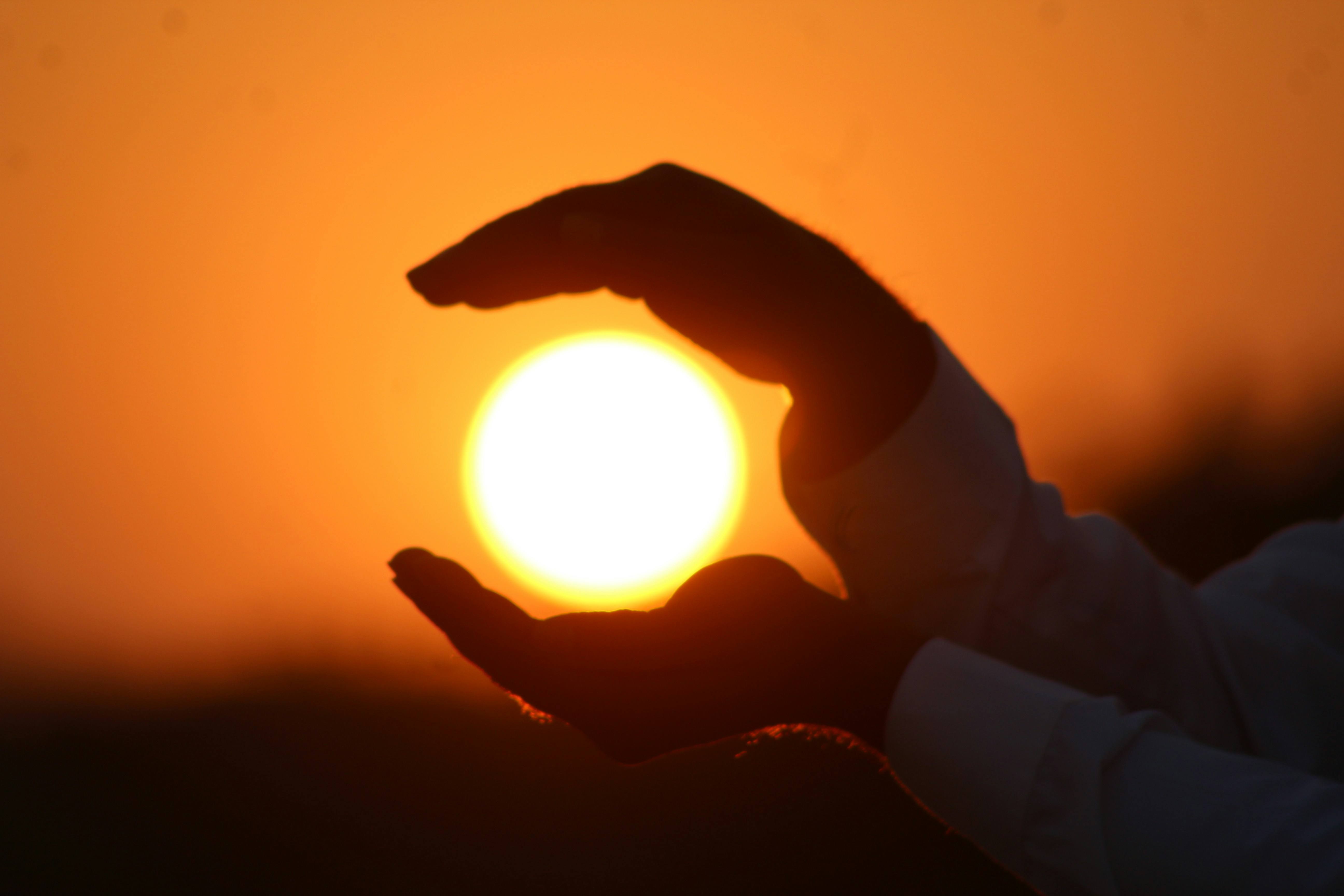 Orb in Hand: A Silhouette at Sunset