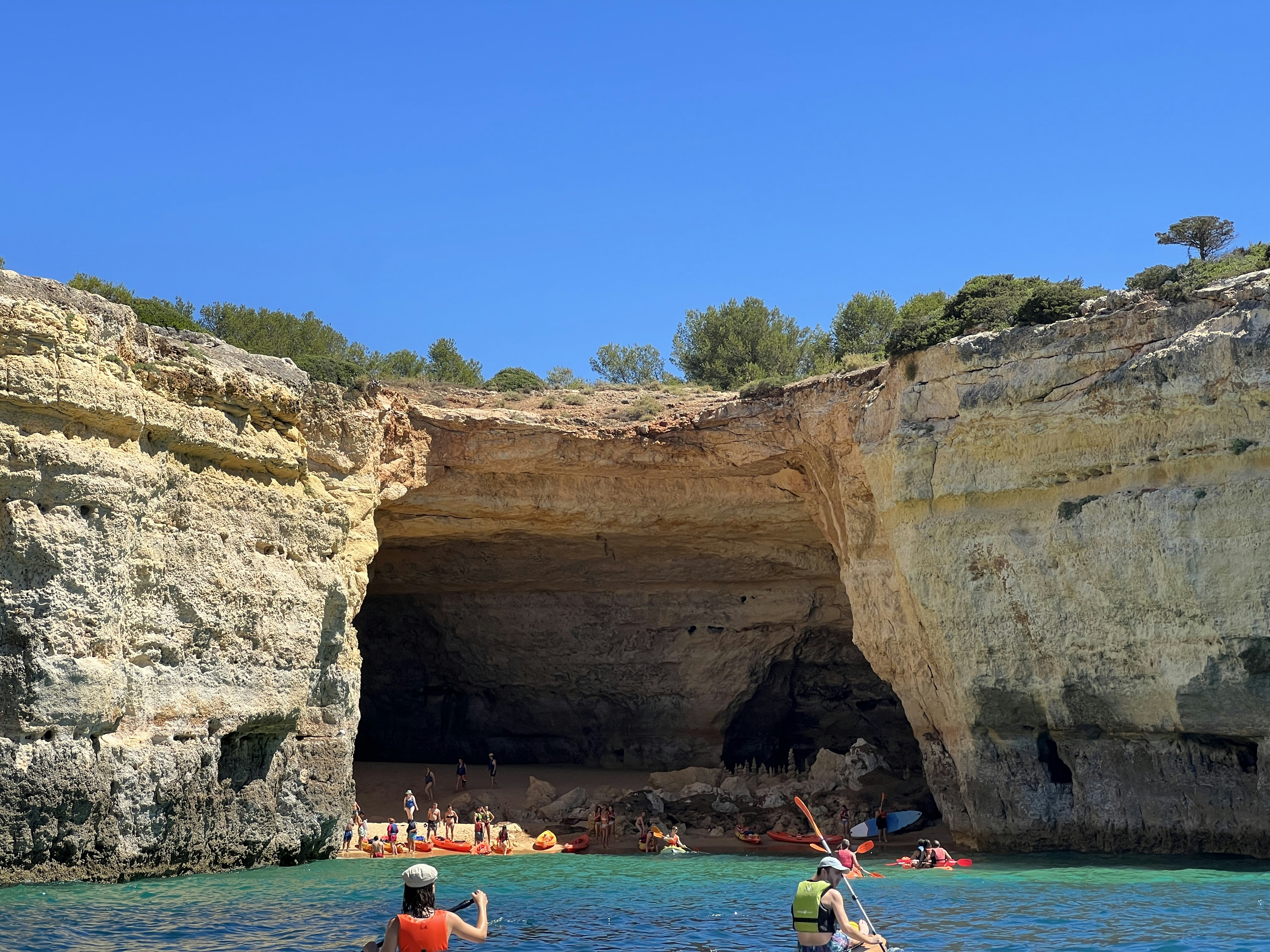 Soaking up the serene beauty of Portugal's Algarve coastline, a group of friends or family members are seen lounging together in the tranquil waters of Benagil Beach.
