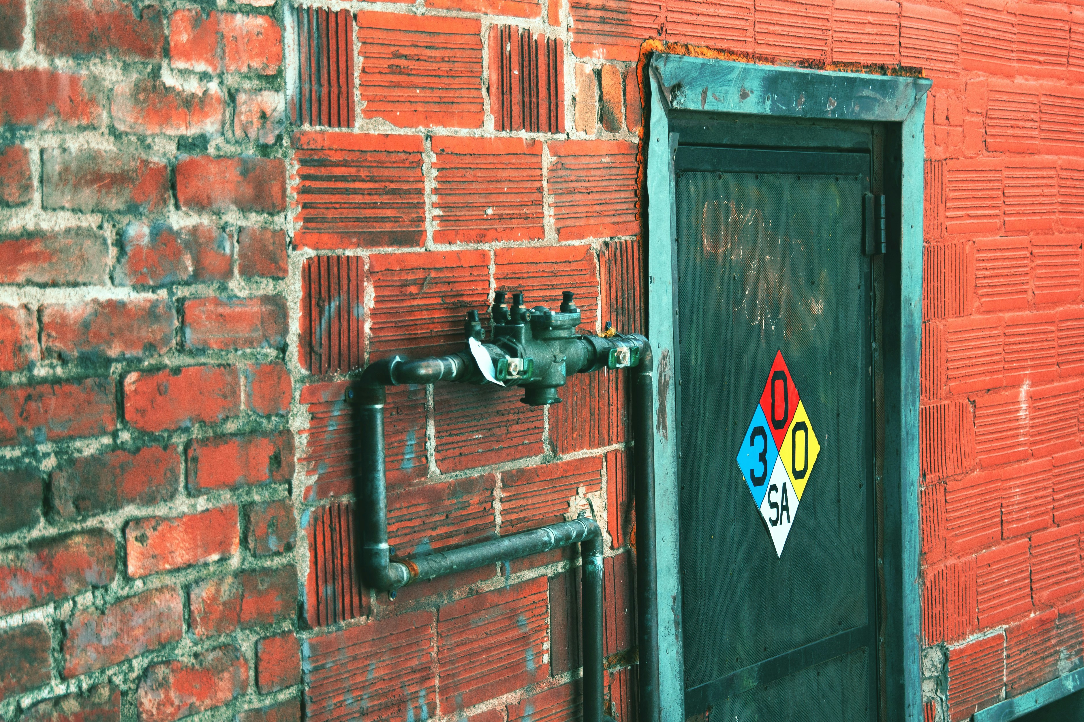 Green door with hazard label on a weathered brick wall