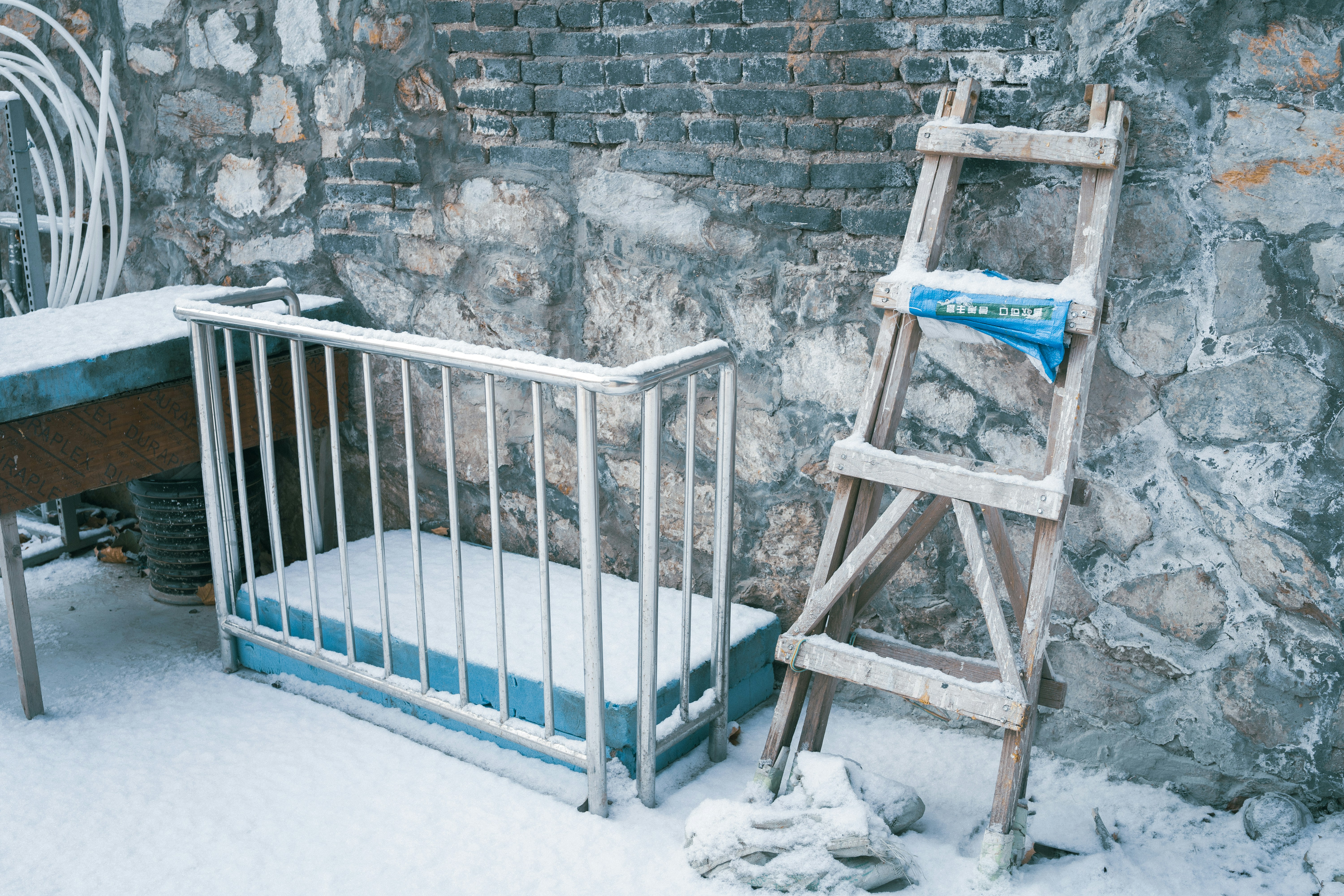 Snowbound Nursery: A Metal Crib and Wooden Ladder Amid Icicled Stone Wall