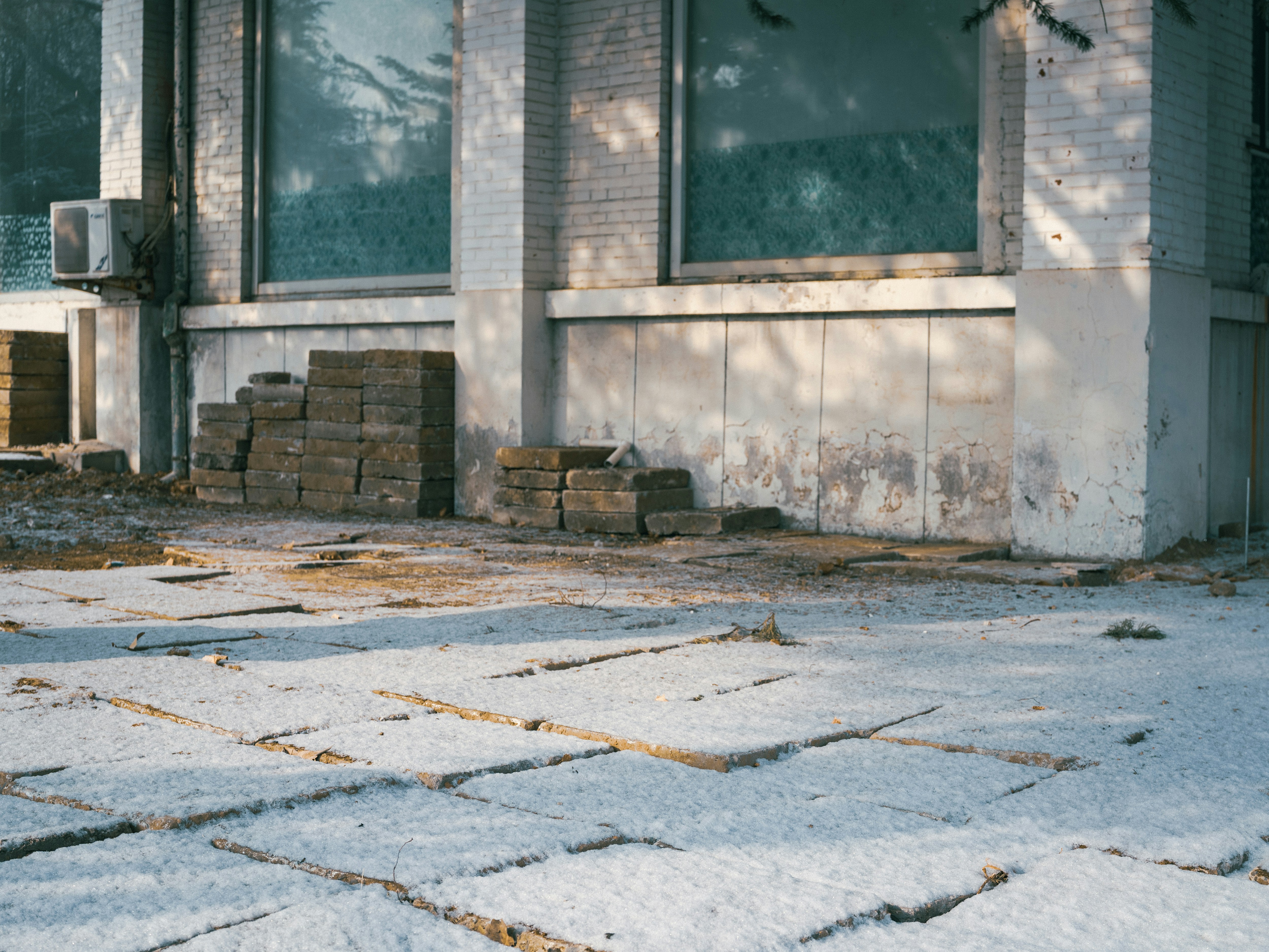 Faded storefront, weathered steps, and scattered debris in winter-light