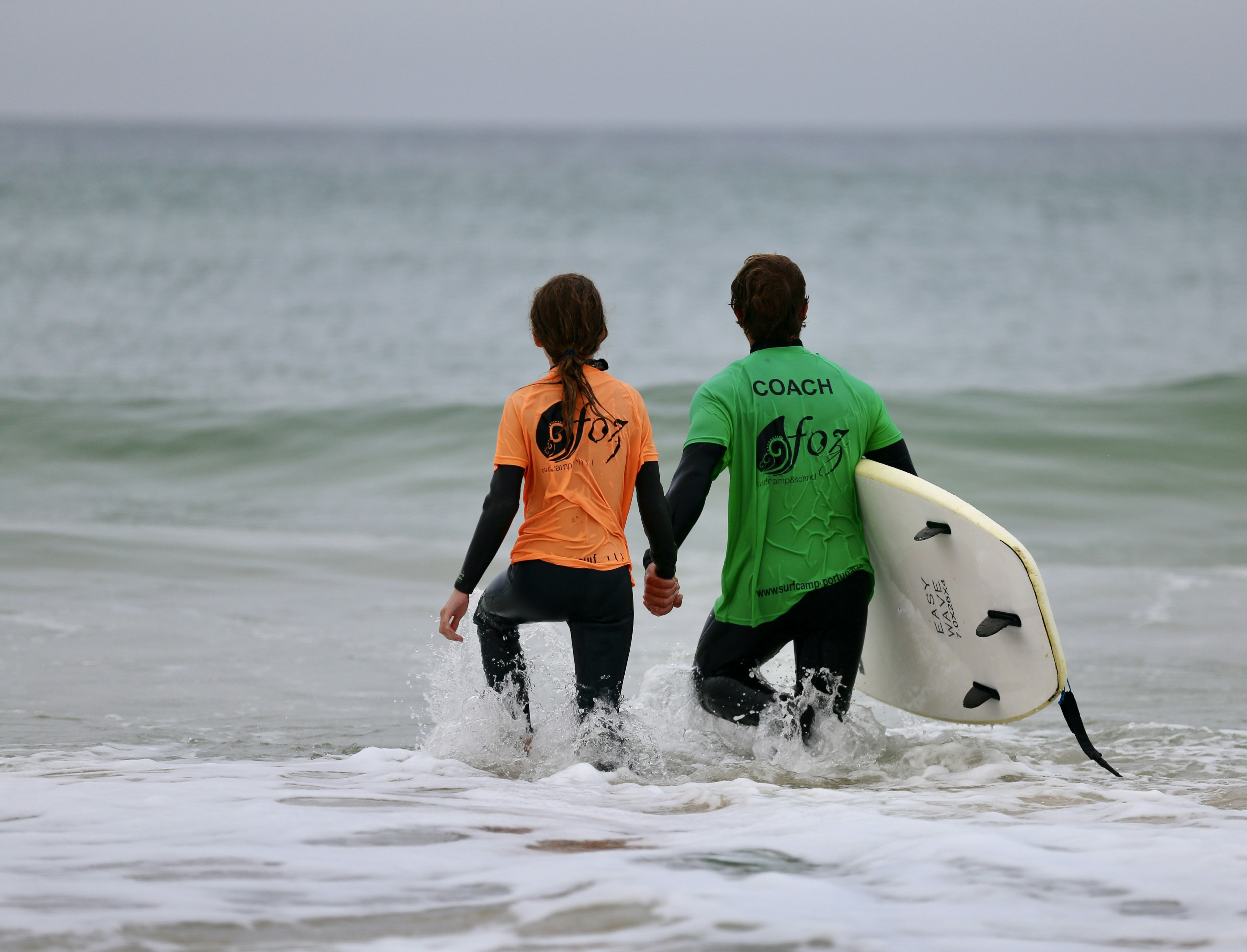 Two Surfers Enter the Surf: Friday Hand-in-Hand Toward the Break