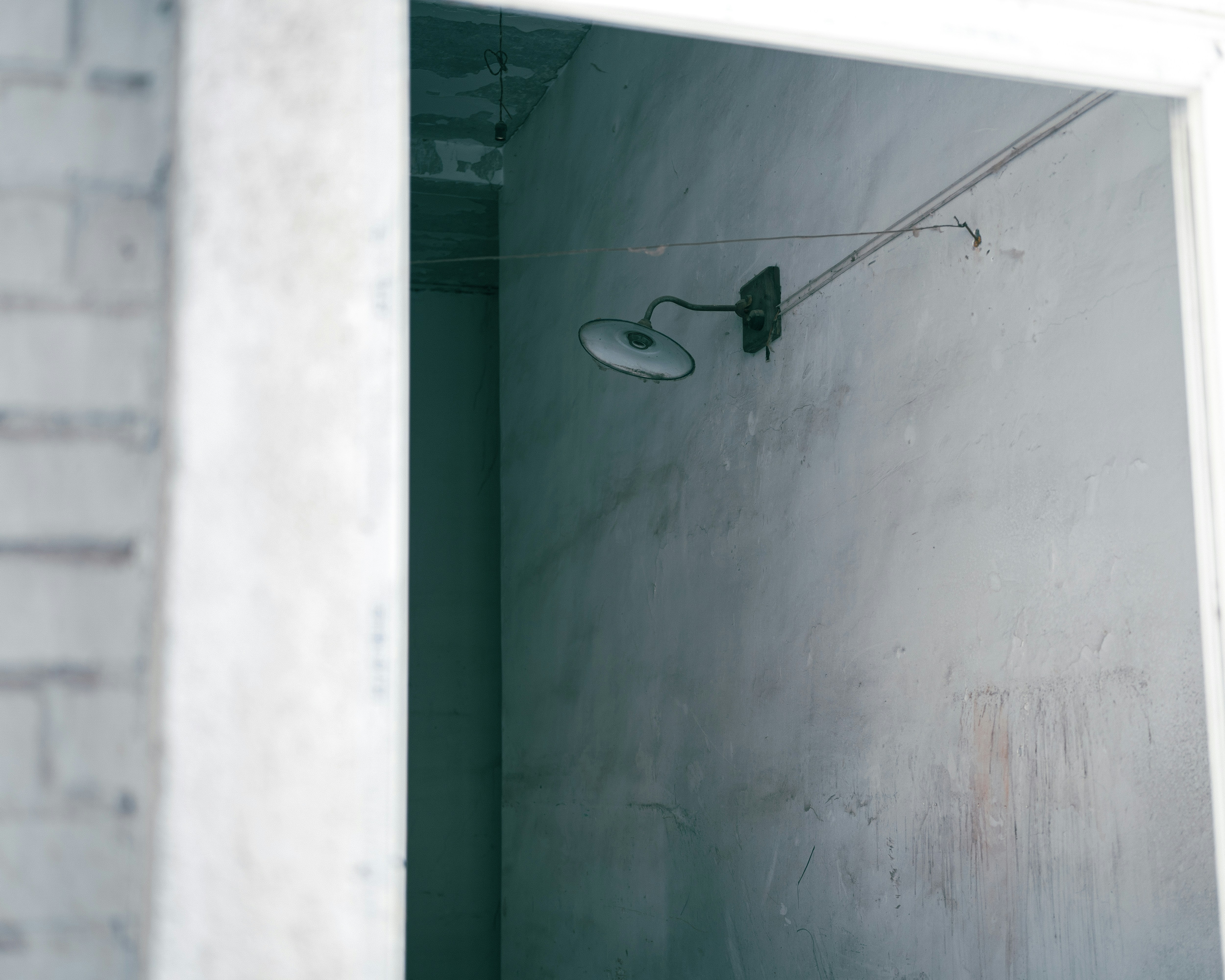 An old shower head in a bare, unfinished room.