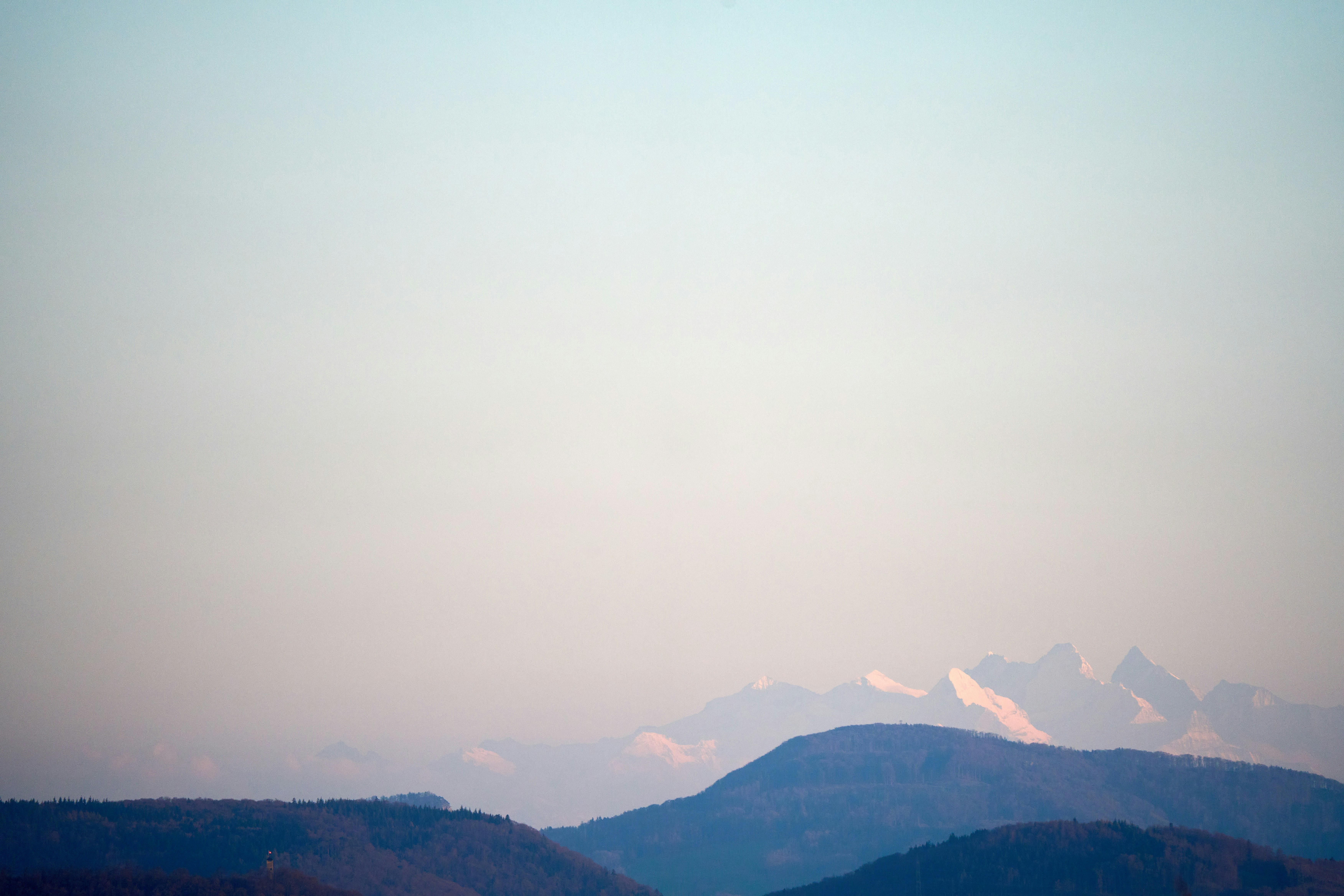 Silent Horizon: Snow-Capped Peaks Beneath a Pale Sunrise