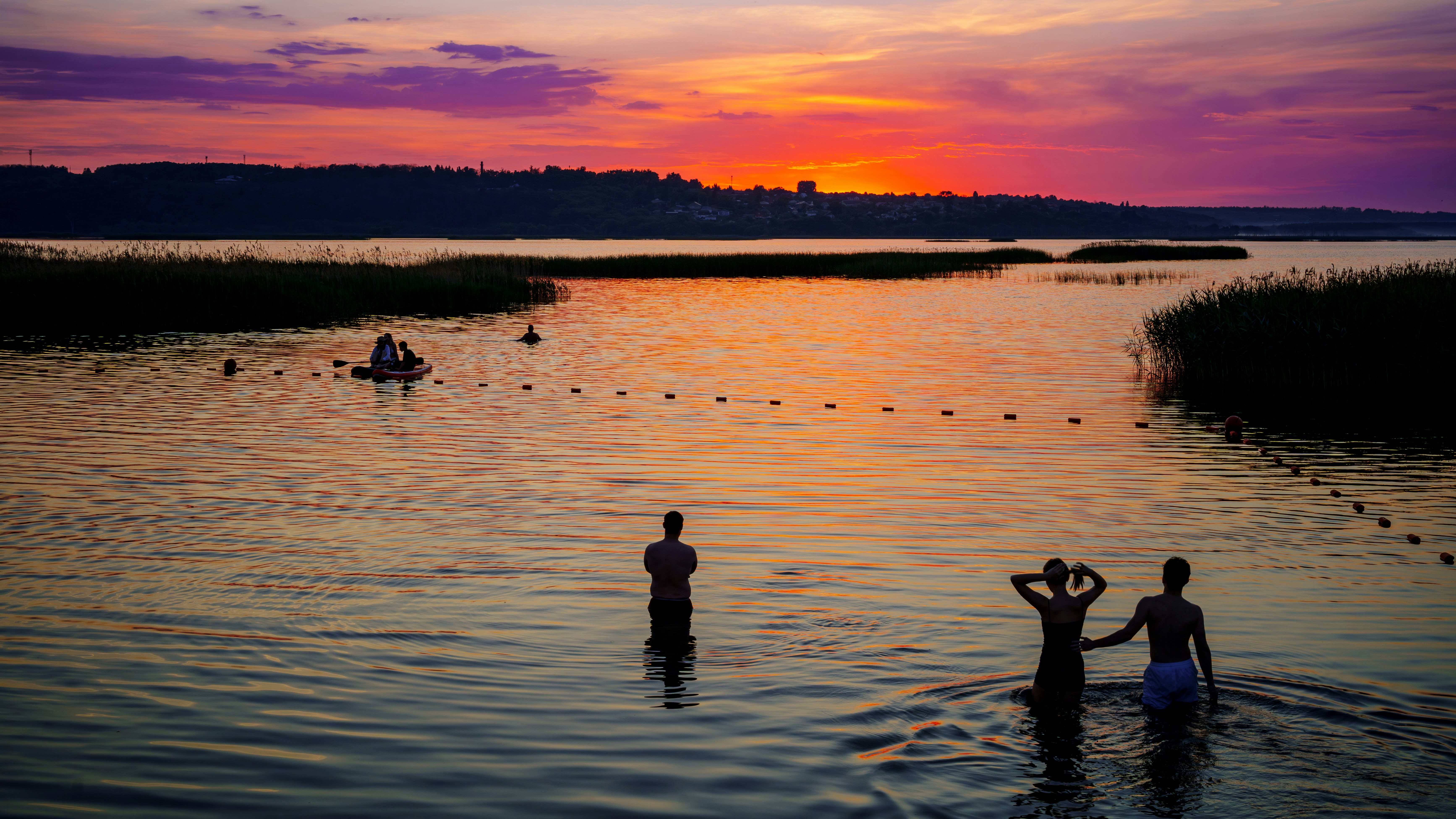 Silhouette at Sunset: Children and Swimmers in Calm Lagoon