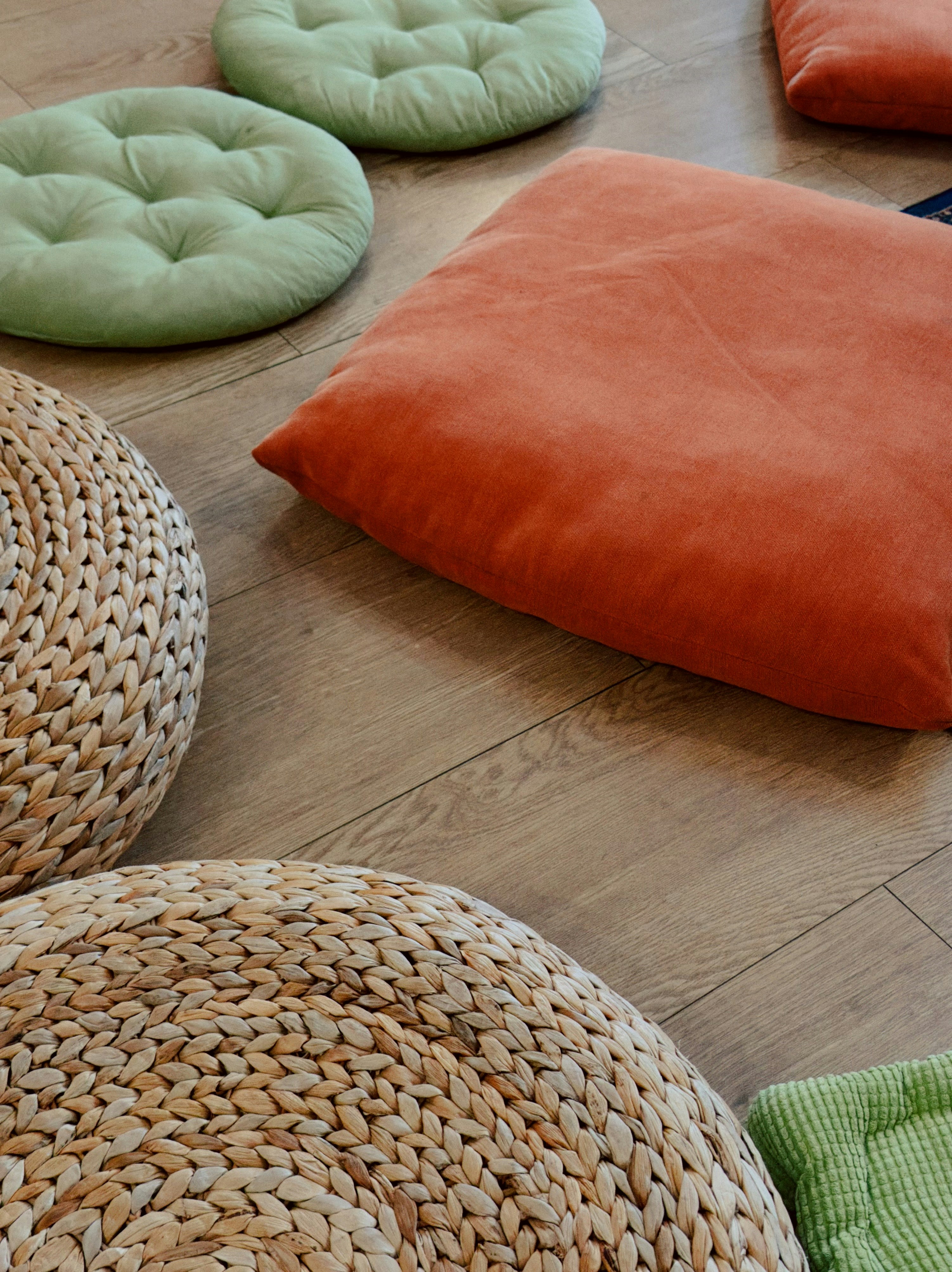 Colorful cushions and woven poufs arranged on a wooden floor.
