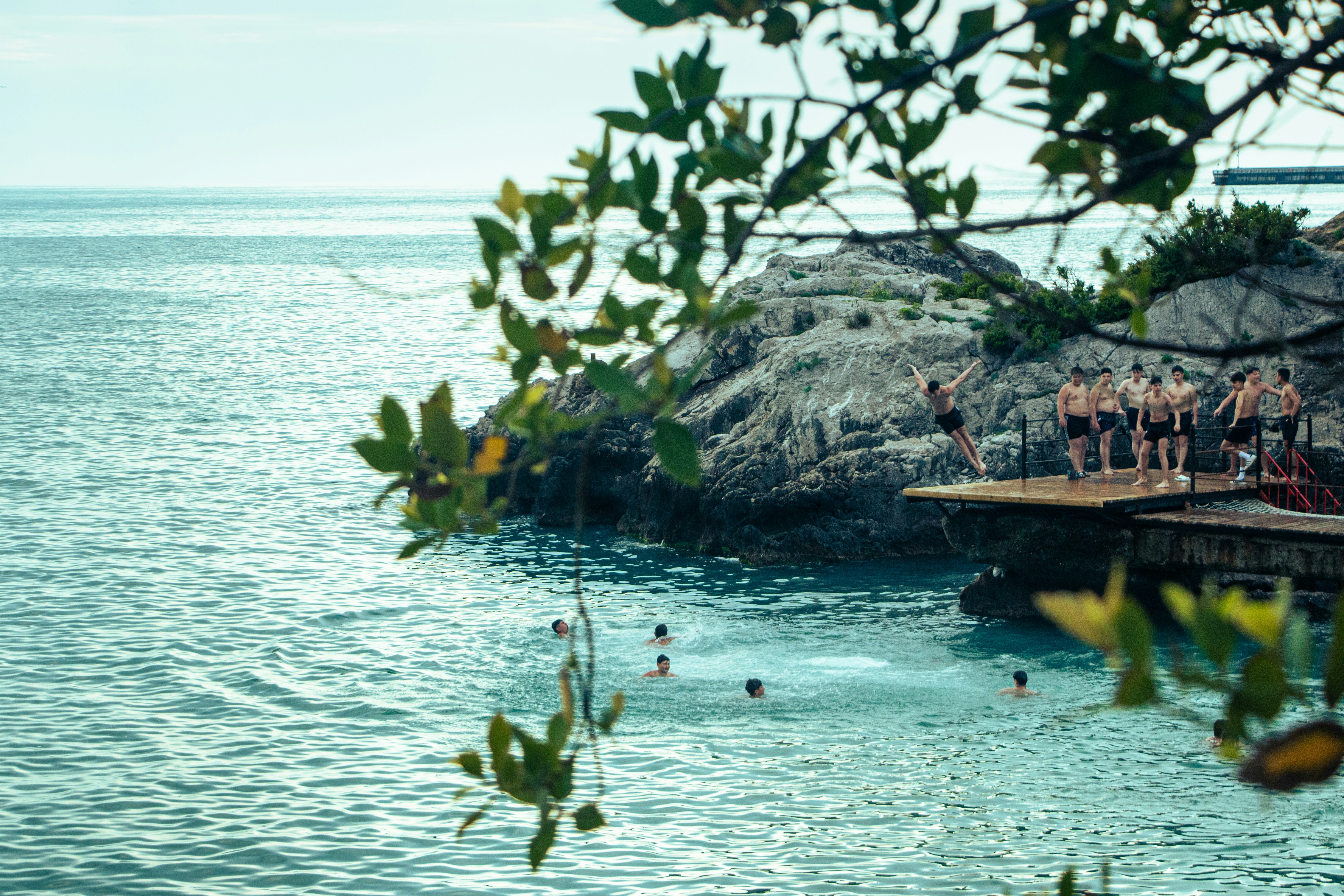 Sunlit Platform Daredevils: A Cliffside Swim Party